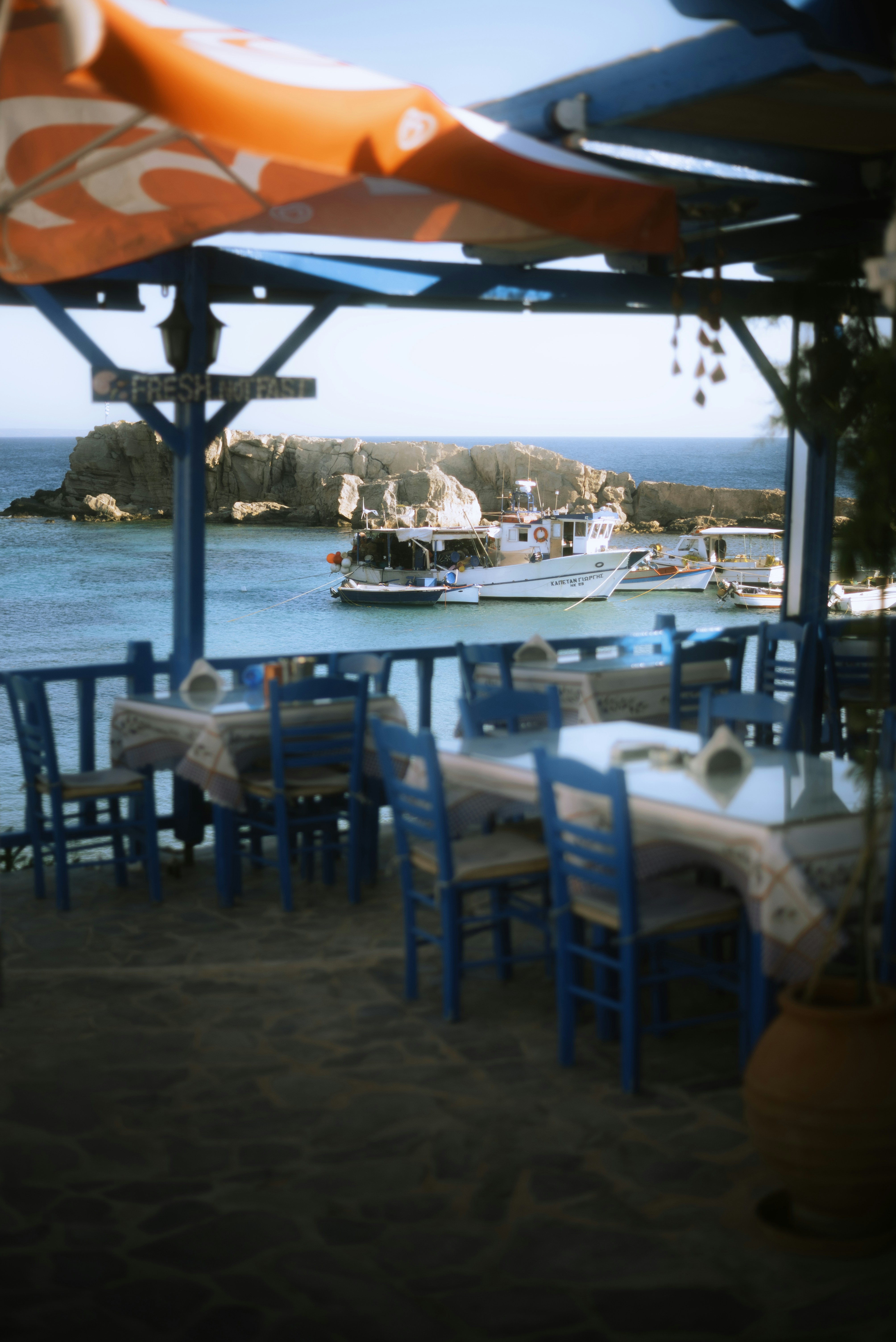 Sea Breeze Café: Boats, Blue Chairs, and Ocean View Through the Pergola