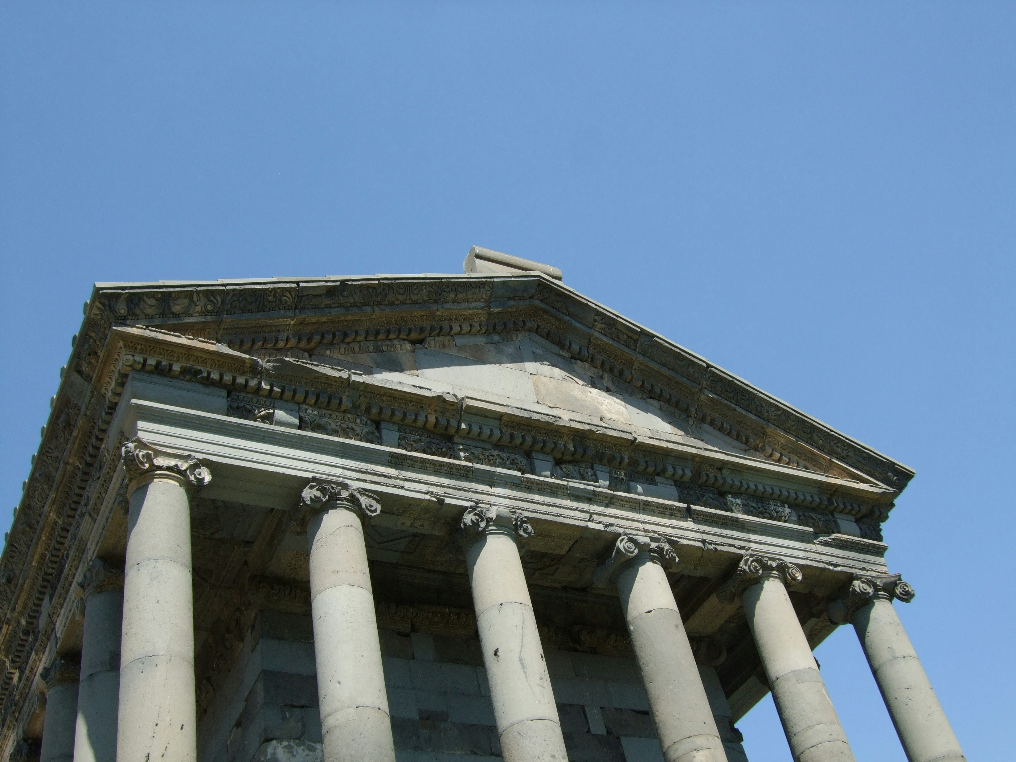 The stone columns and pediment of a classical temple against a clear blue sky