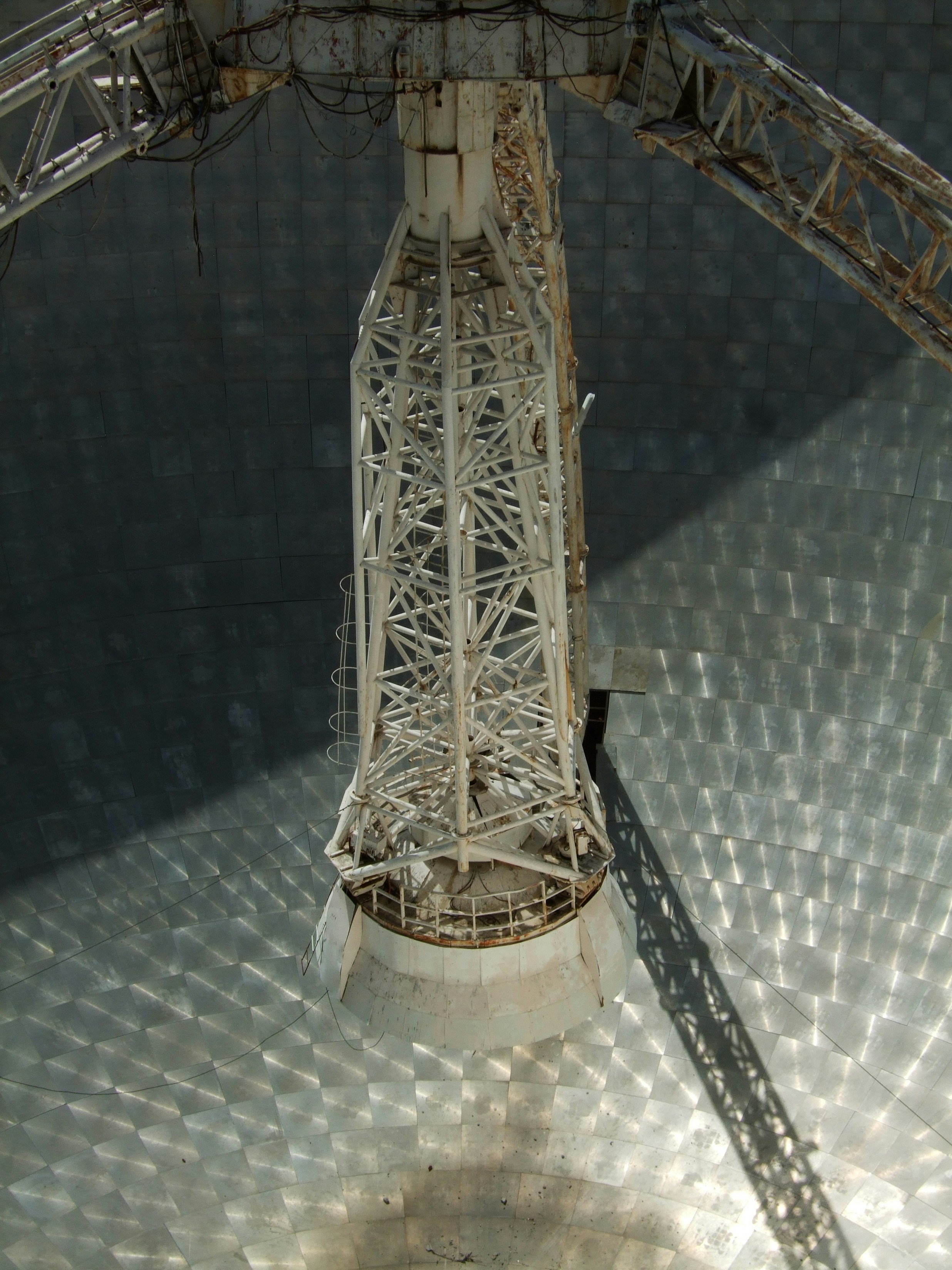 A large white metal radio telescope dish with a central support structure