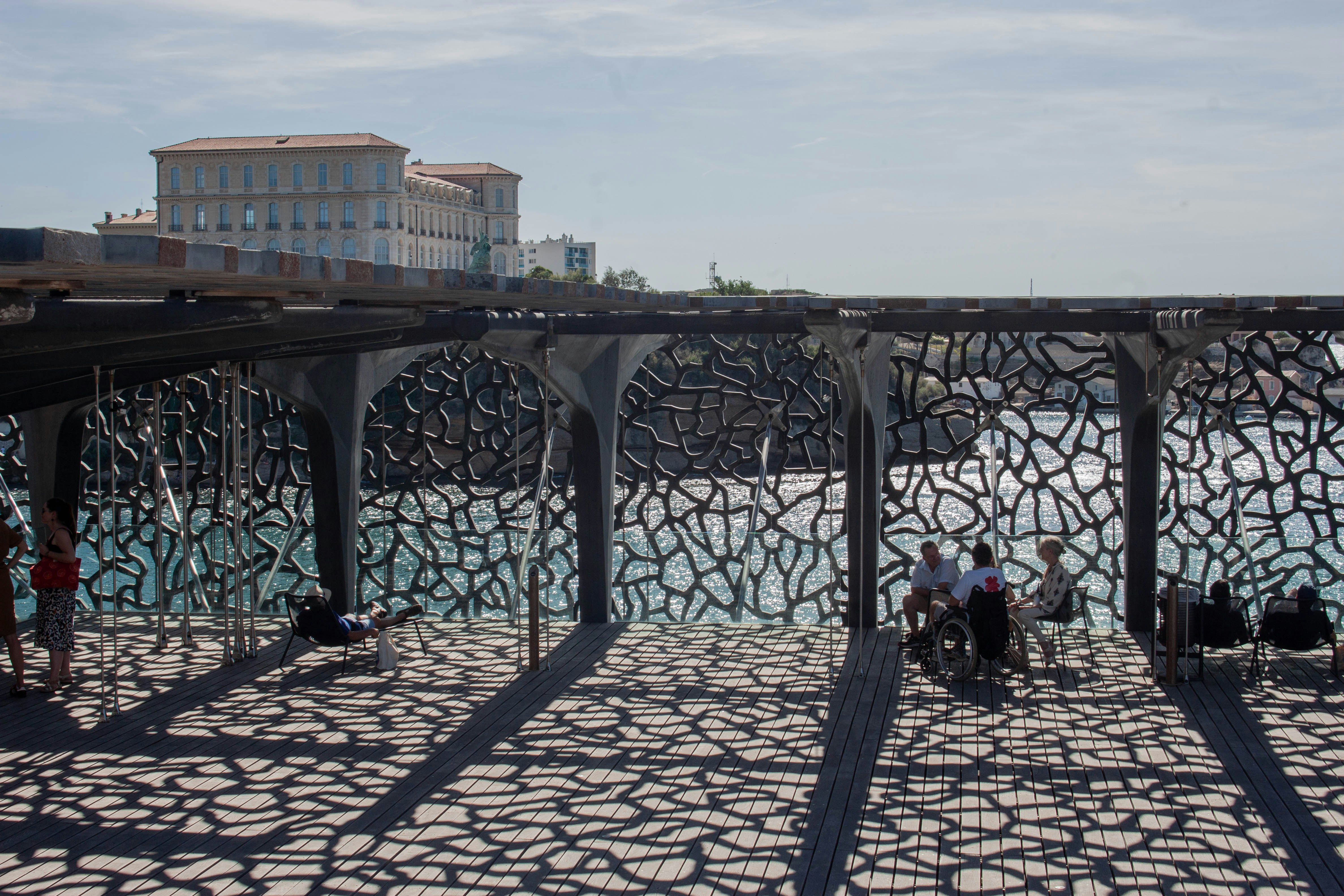 Shadows on a latticed promenade by turquoise waters