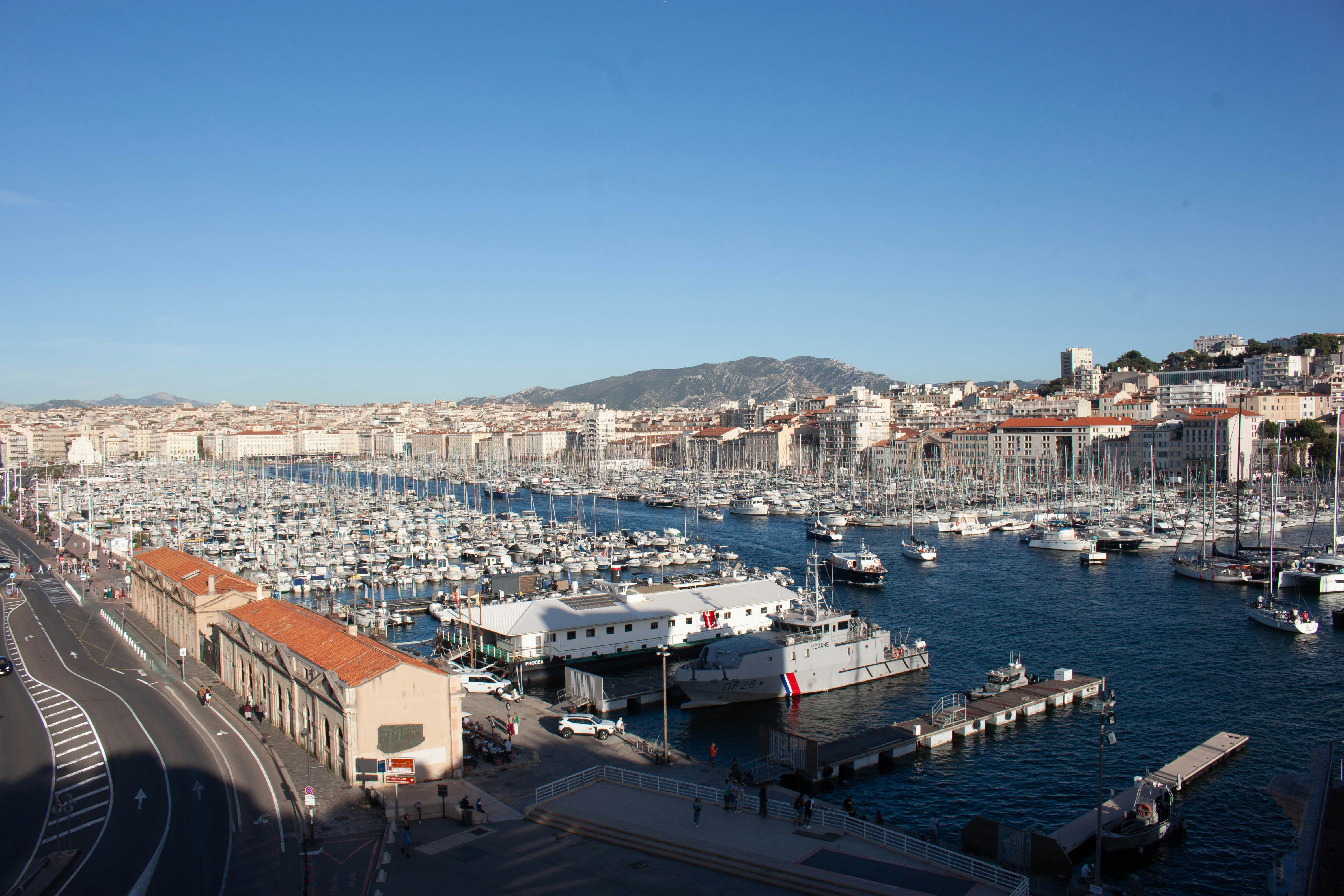 Harbor Mosaic: Boats, Promenade, and Rooftops under a Blue Sky
