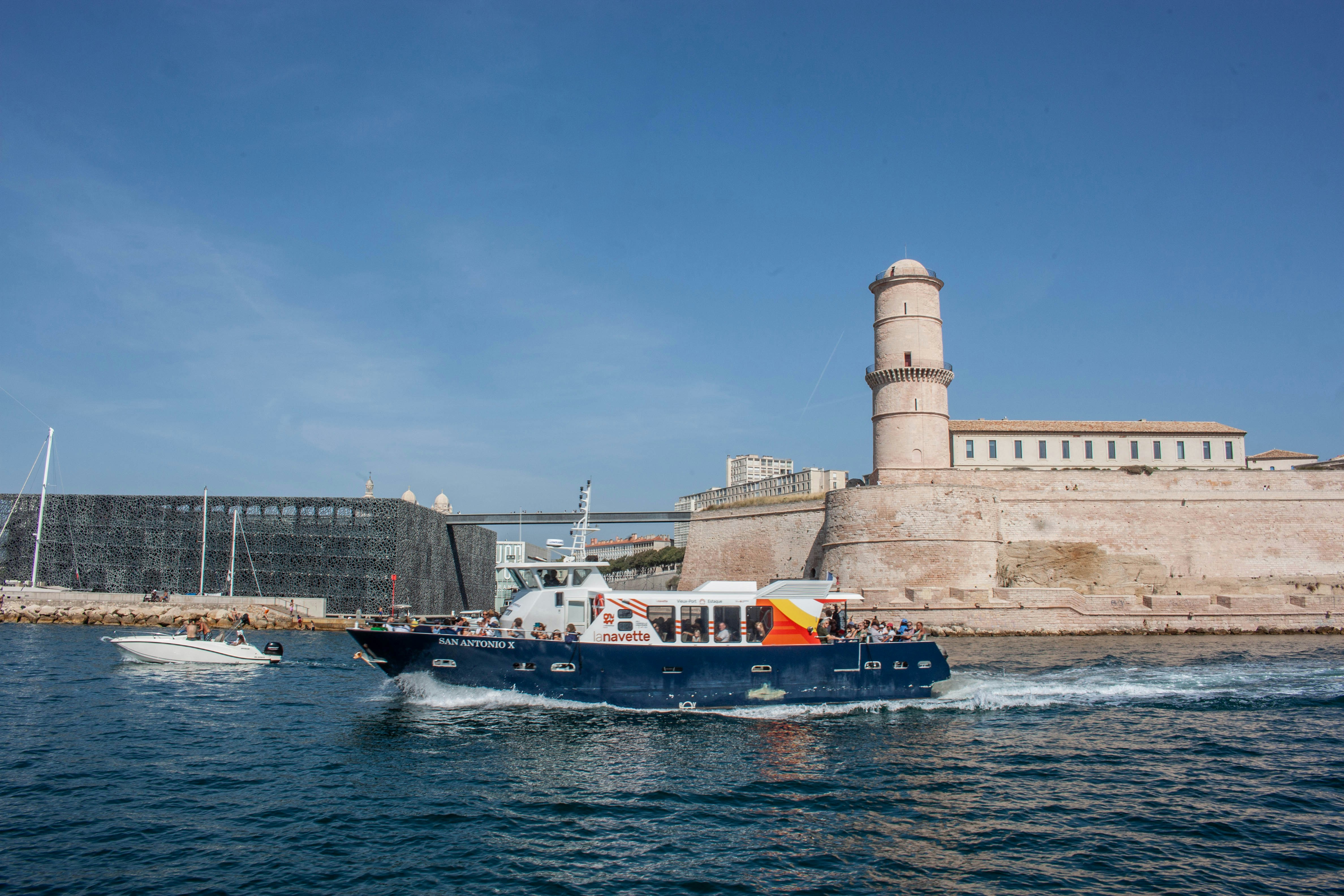 Coastal Patrol: A Blue Vessel Rounds the Fortified Harbor