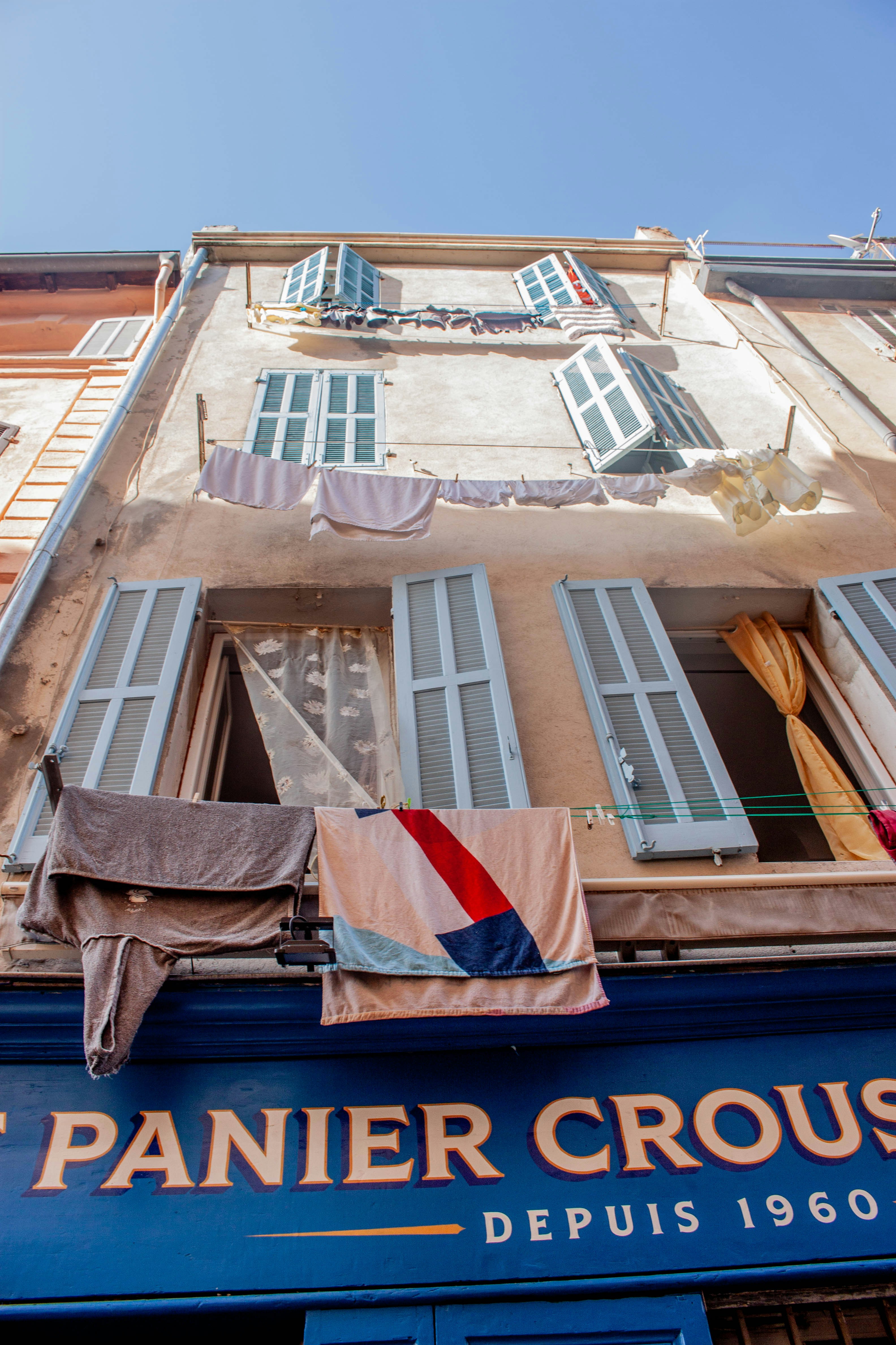 Linen and Laundry on the Facade: A Parisian Laundry Scene Above a Vintage Blue Sign