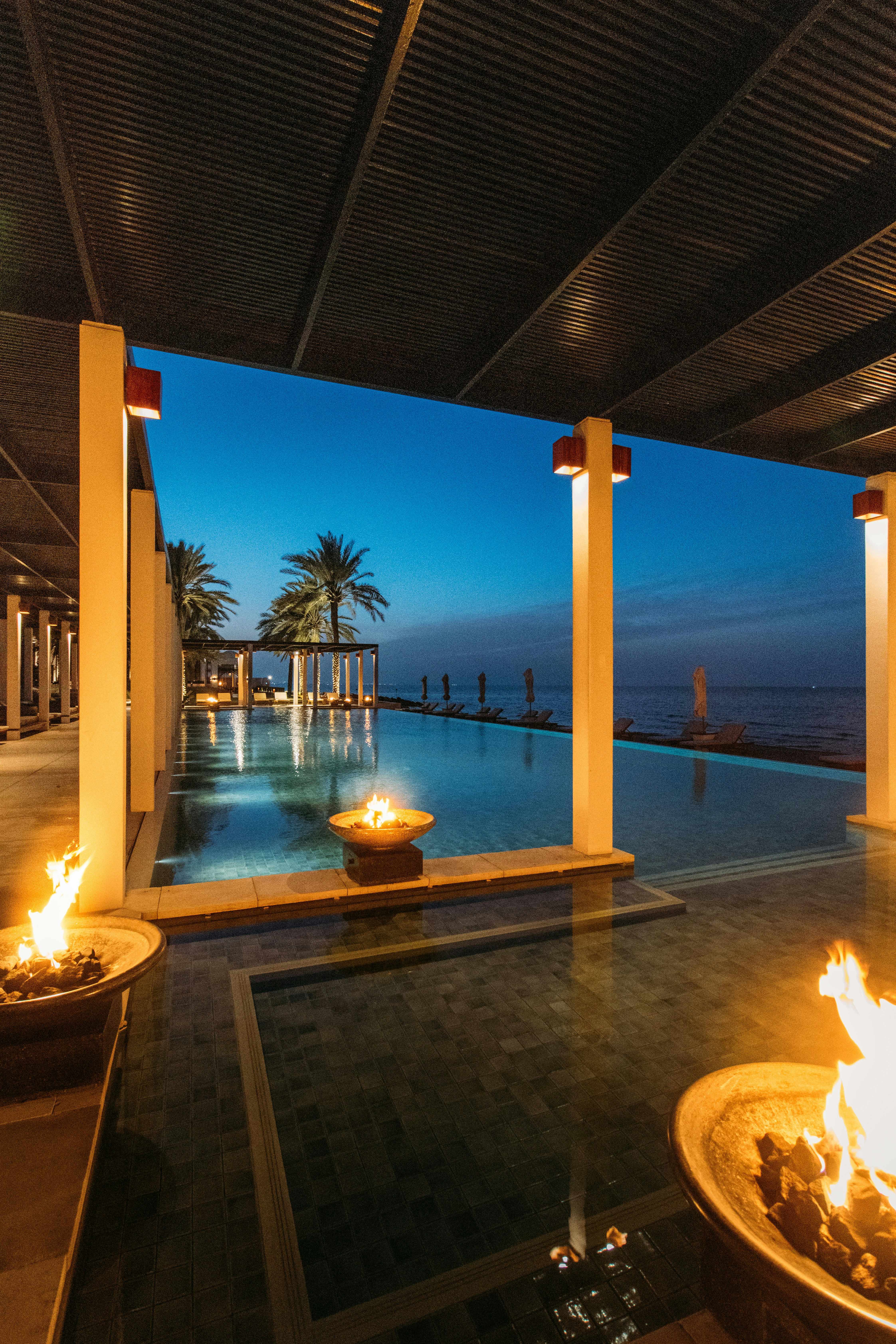 Evening Oasis: Fire Torches Framing a Poolside Terrace by the Sea