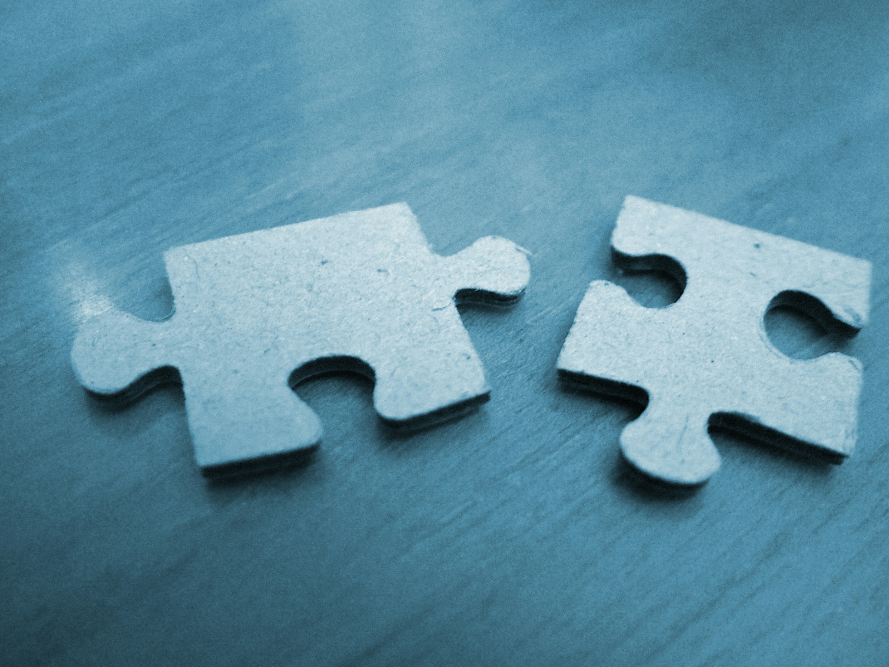 Two blue puzzle pieces separated on a wooden surface