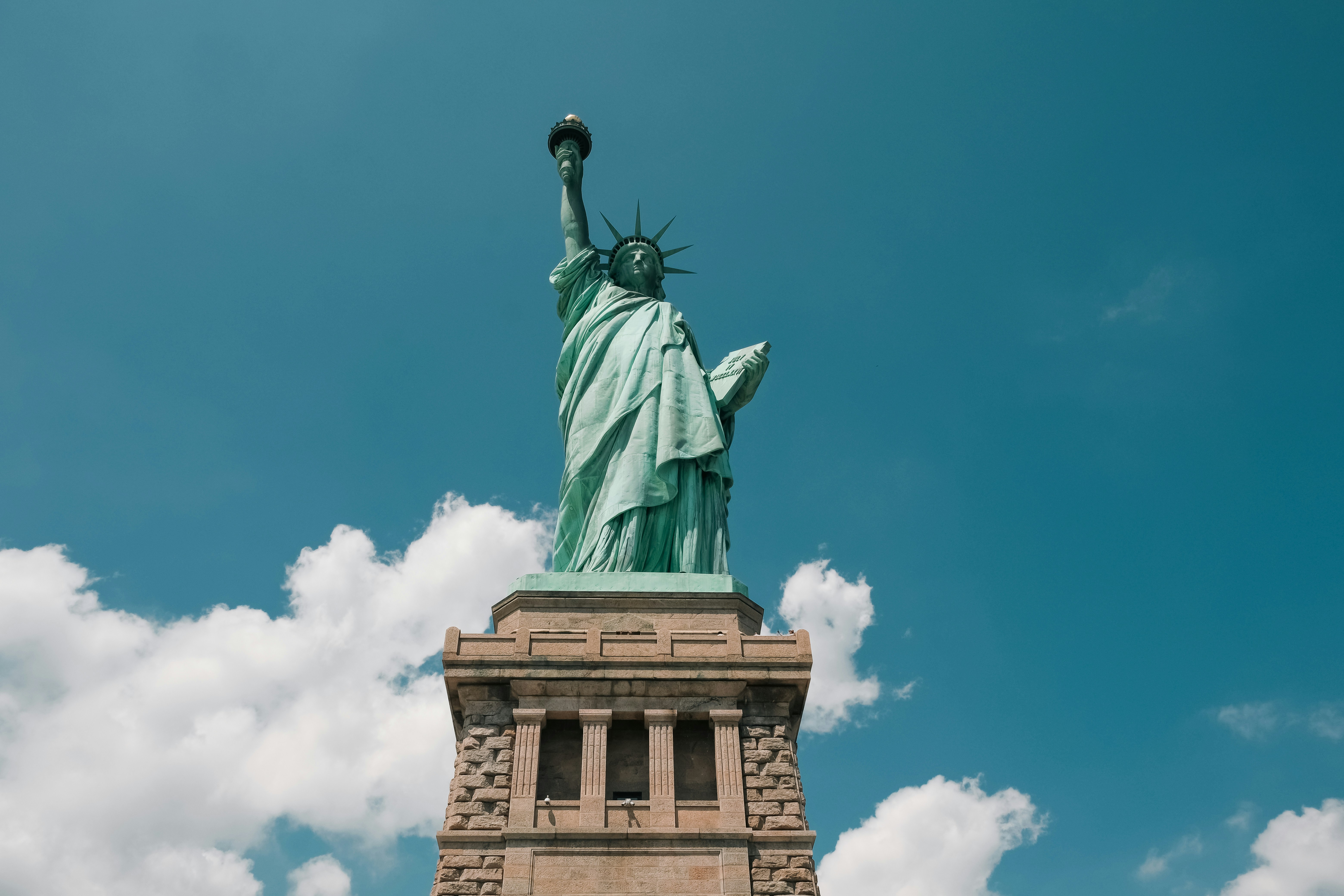 Liberty Rising: The Statue's Crown Amid Sky and Clouds