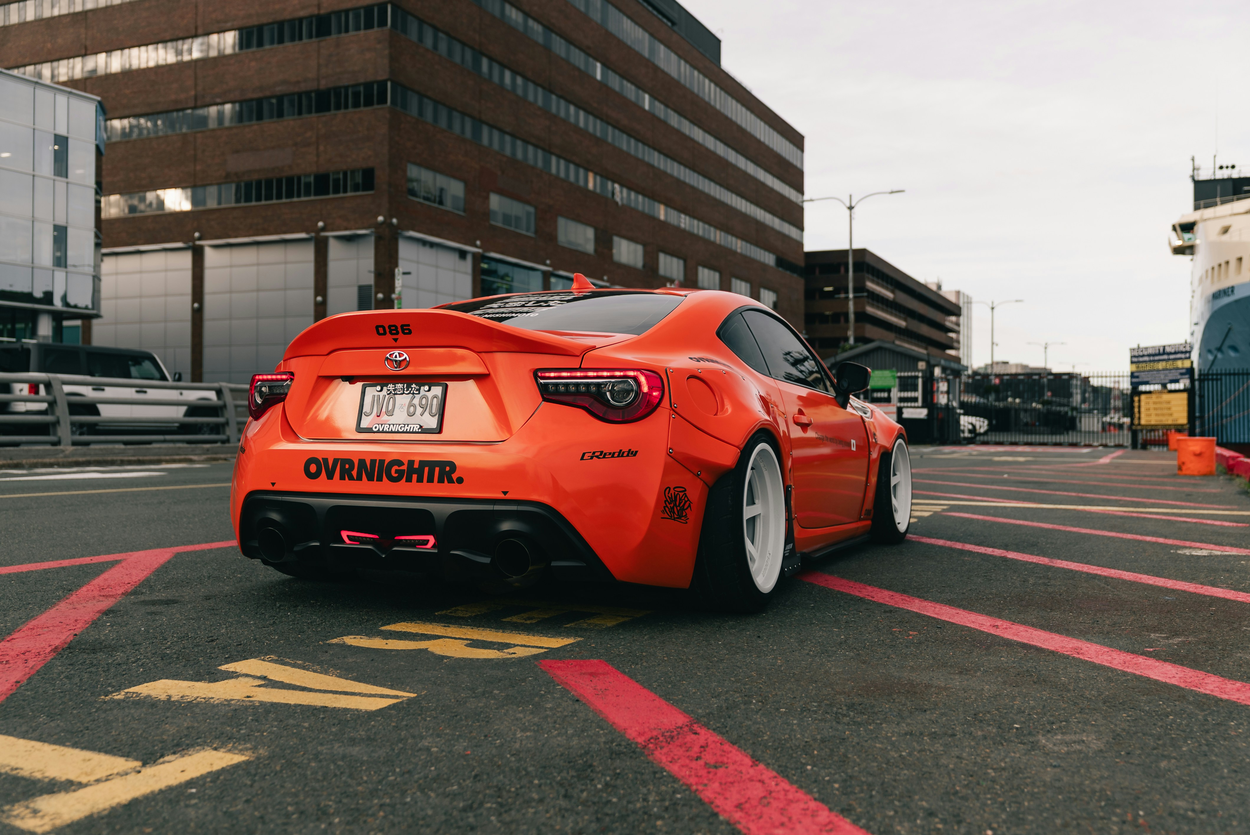 Scarlet Velocity: A Low-A angle of a Custom Red Sports Coupe in an Urban Slipstream