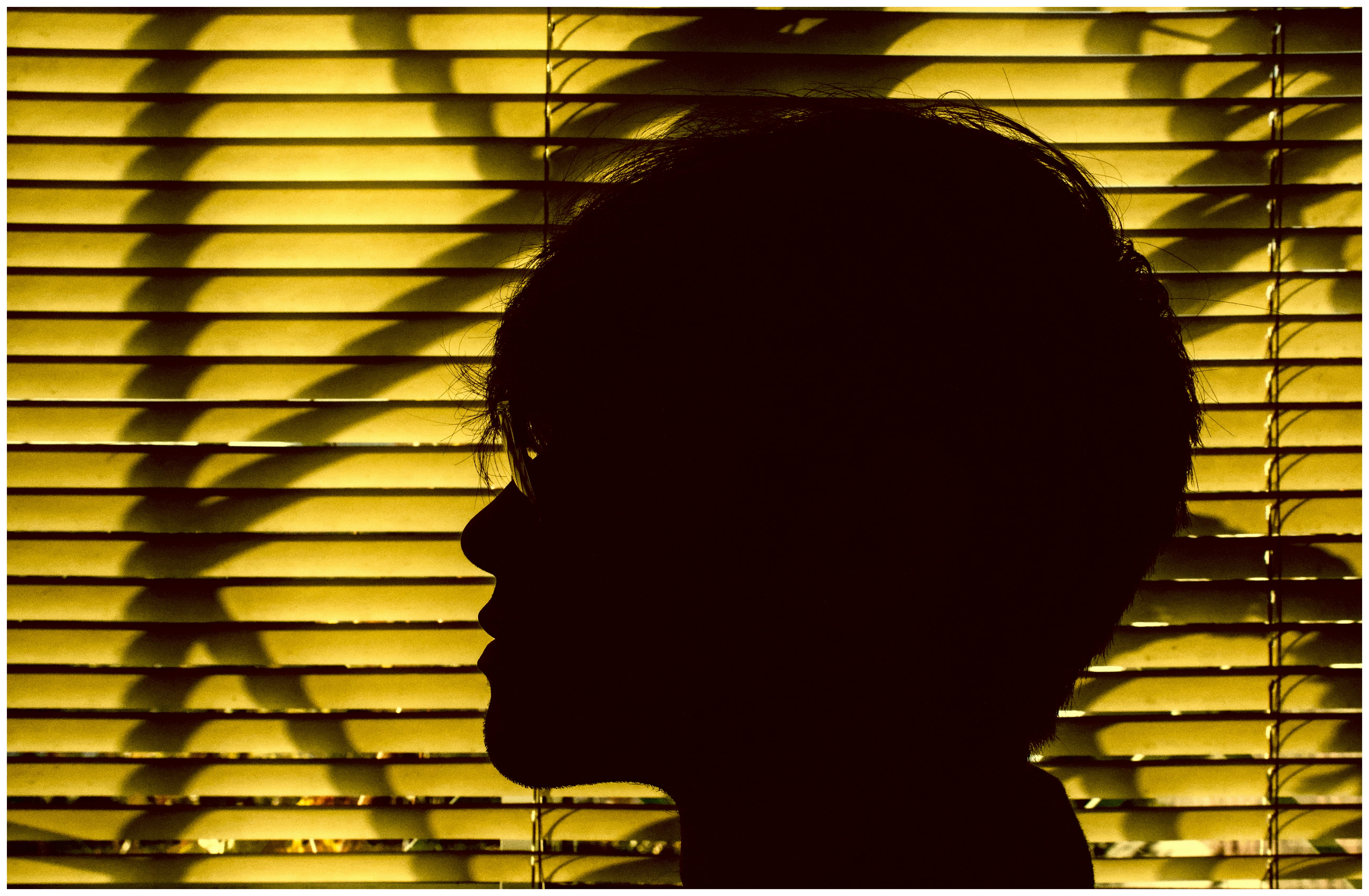 Silhouette of a Child Against Backlit Blind Shadows