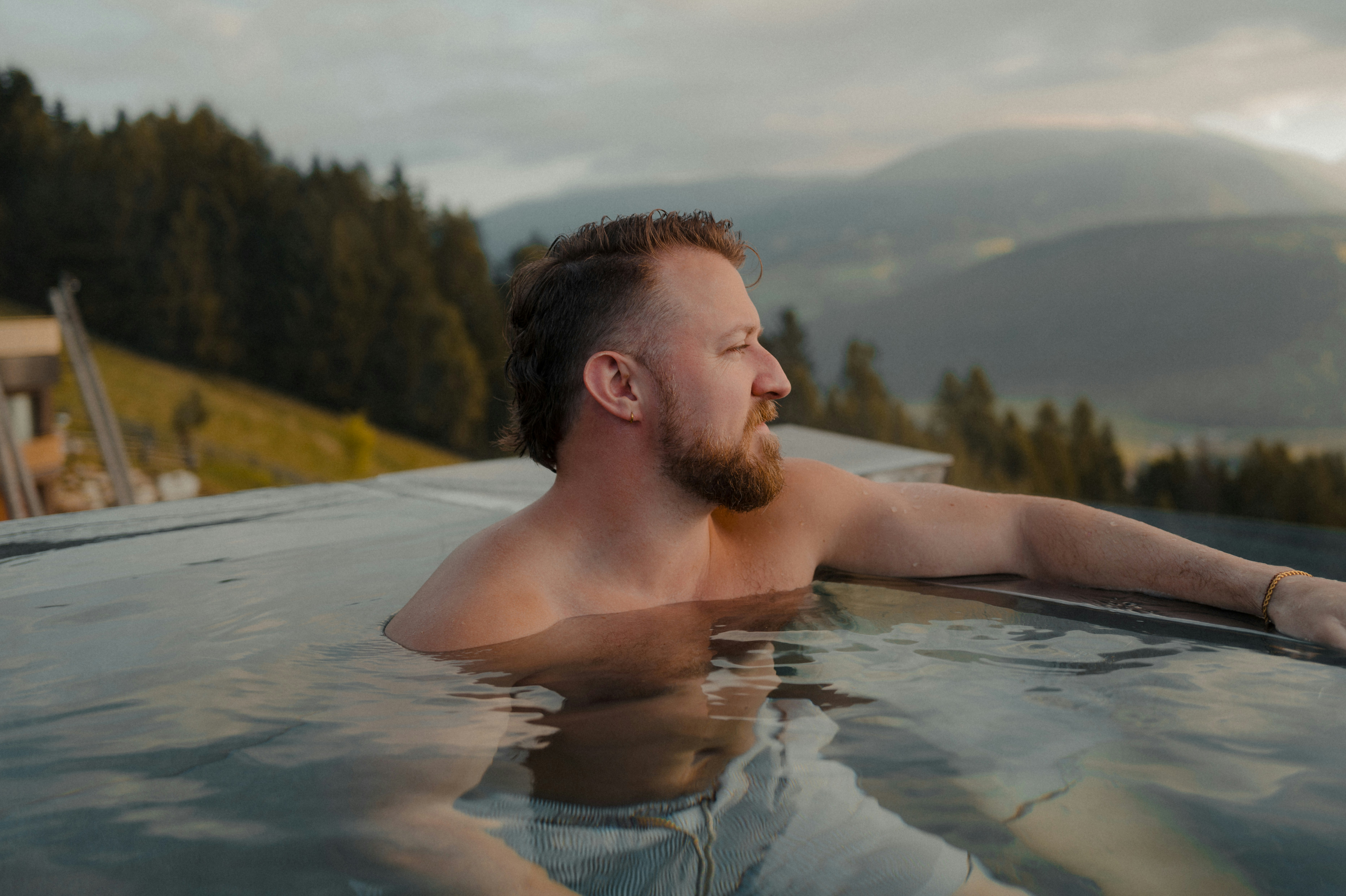 Sunlit Refuge: A Man in an Infinity Pool Against a Mountain Backdrop