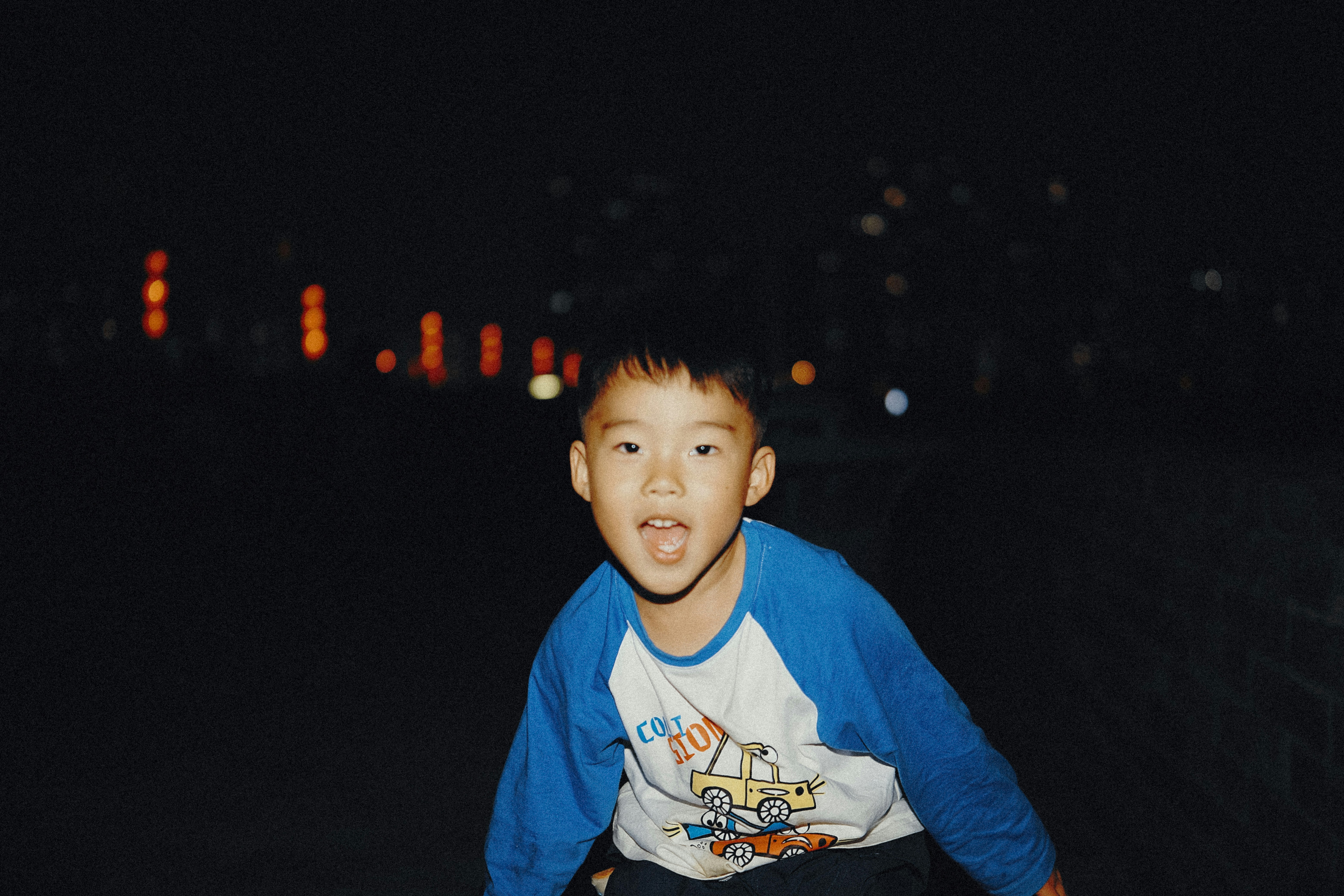 Nighttime grin: a boy lights up the playground edge