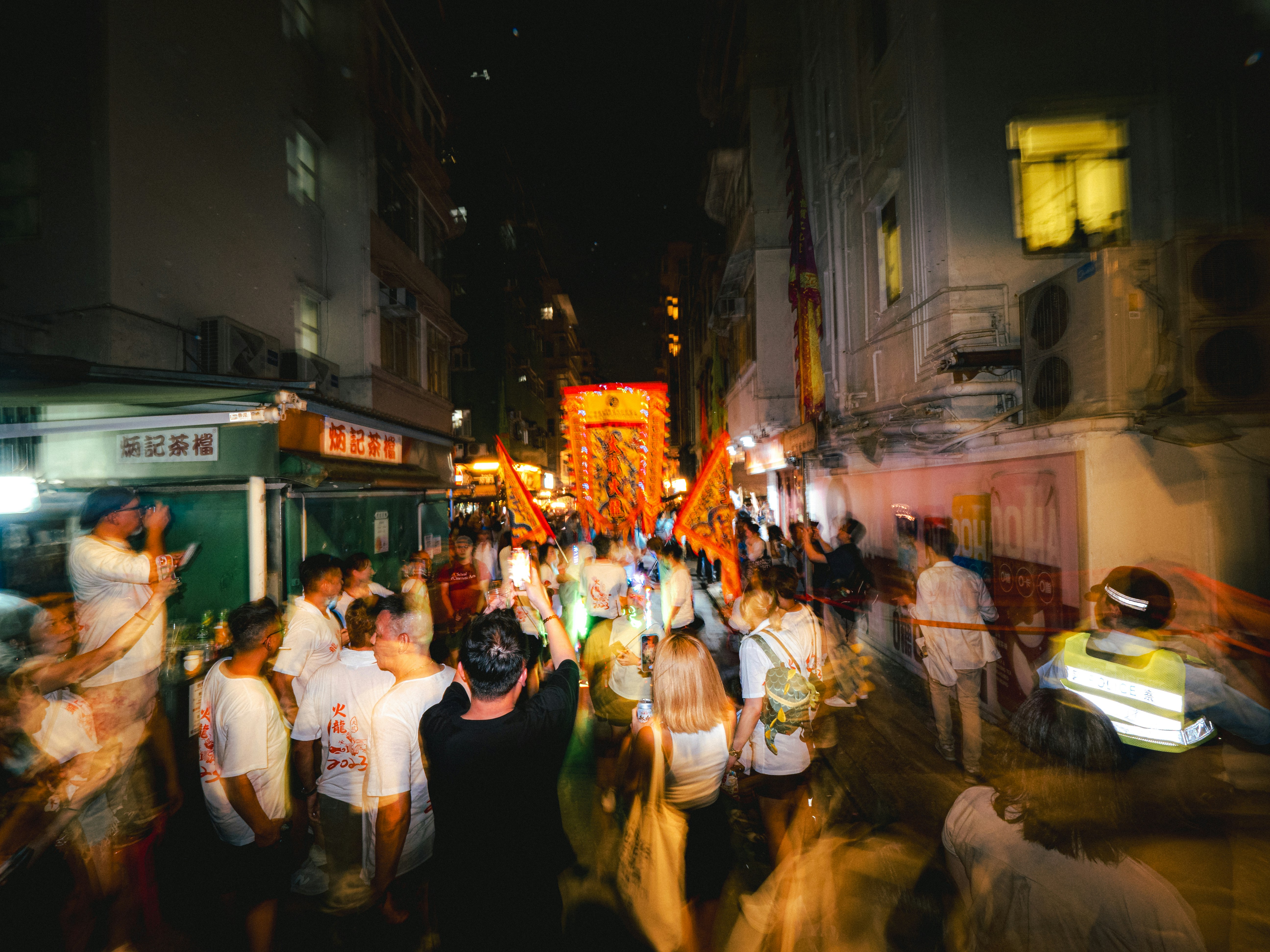 A crowd of people in white shirts following a glowing dragon parade at night