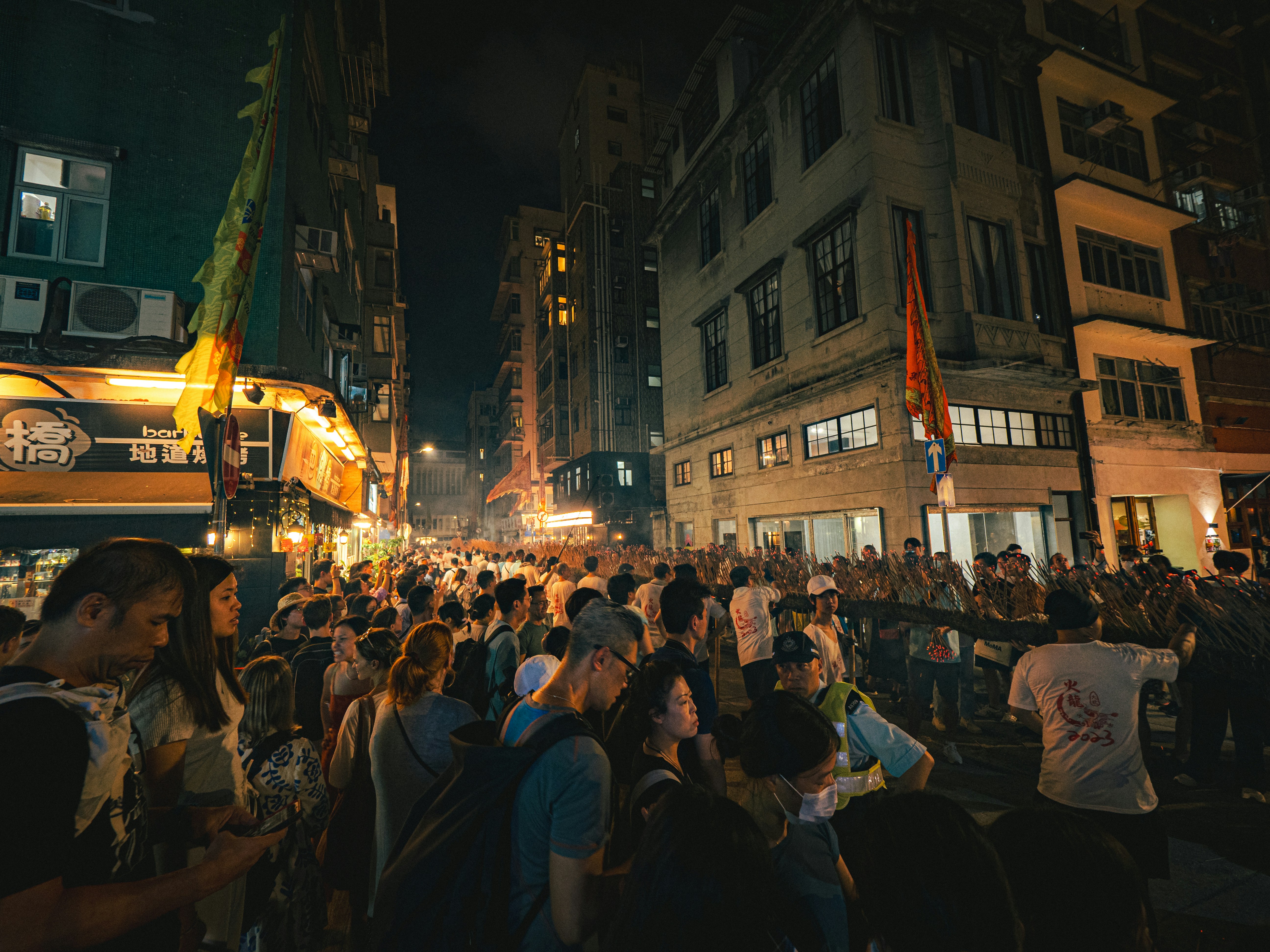 A crowd of people watching a fire dragon dance on a city street at night