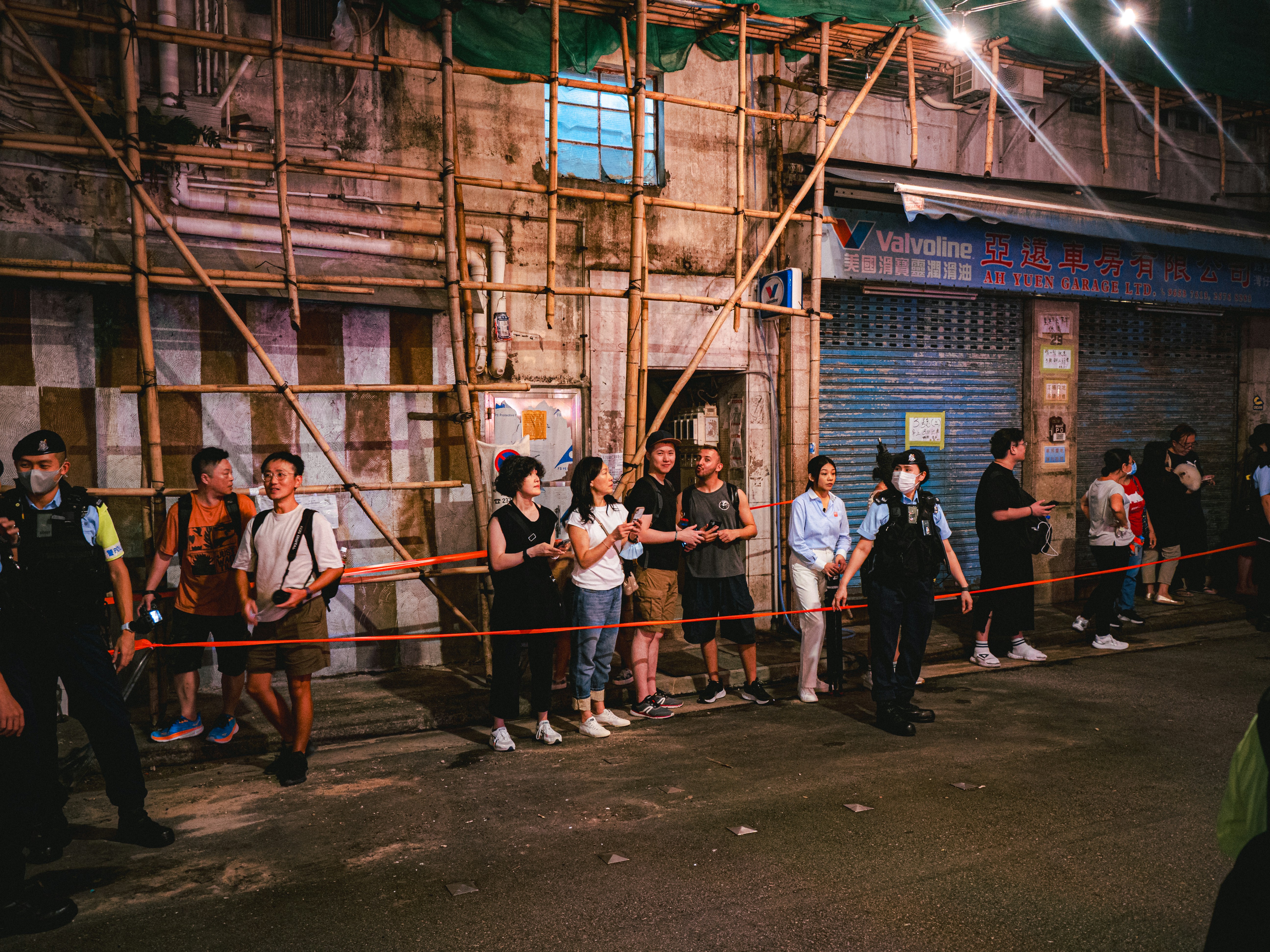Rope-lined Queue Under Industrial Neon: Night Watch at the Closed Street Market