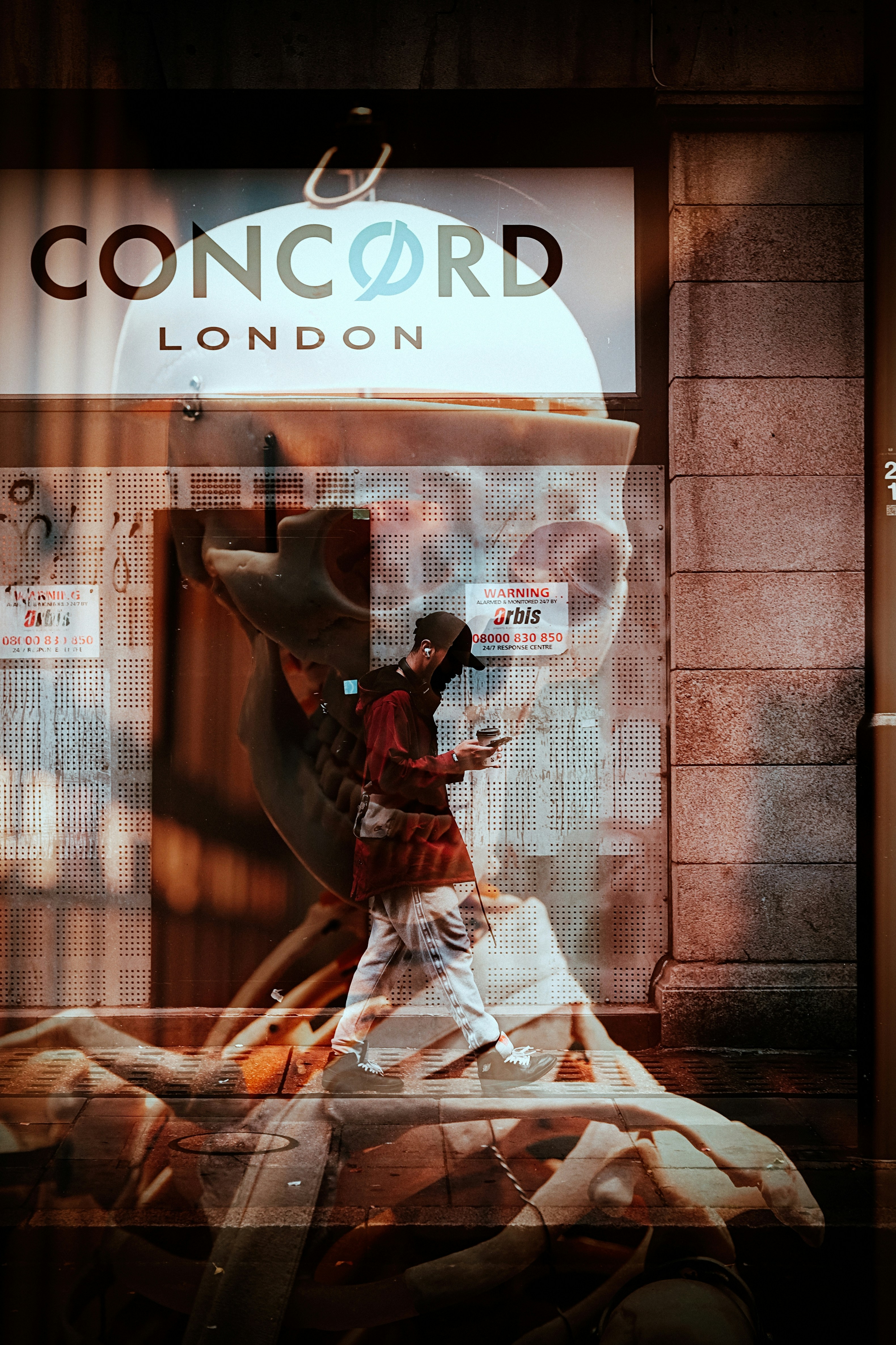 Double Exposure Walk: A Subject in Motion Through a Converging Storefront Reflection