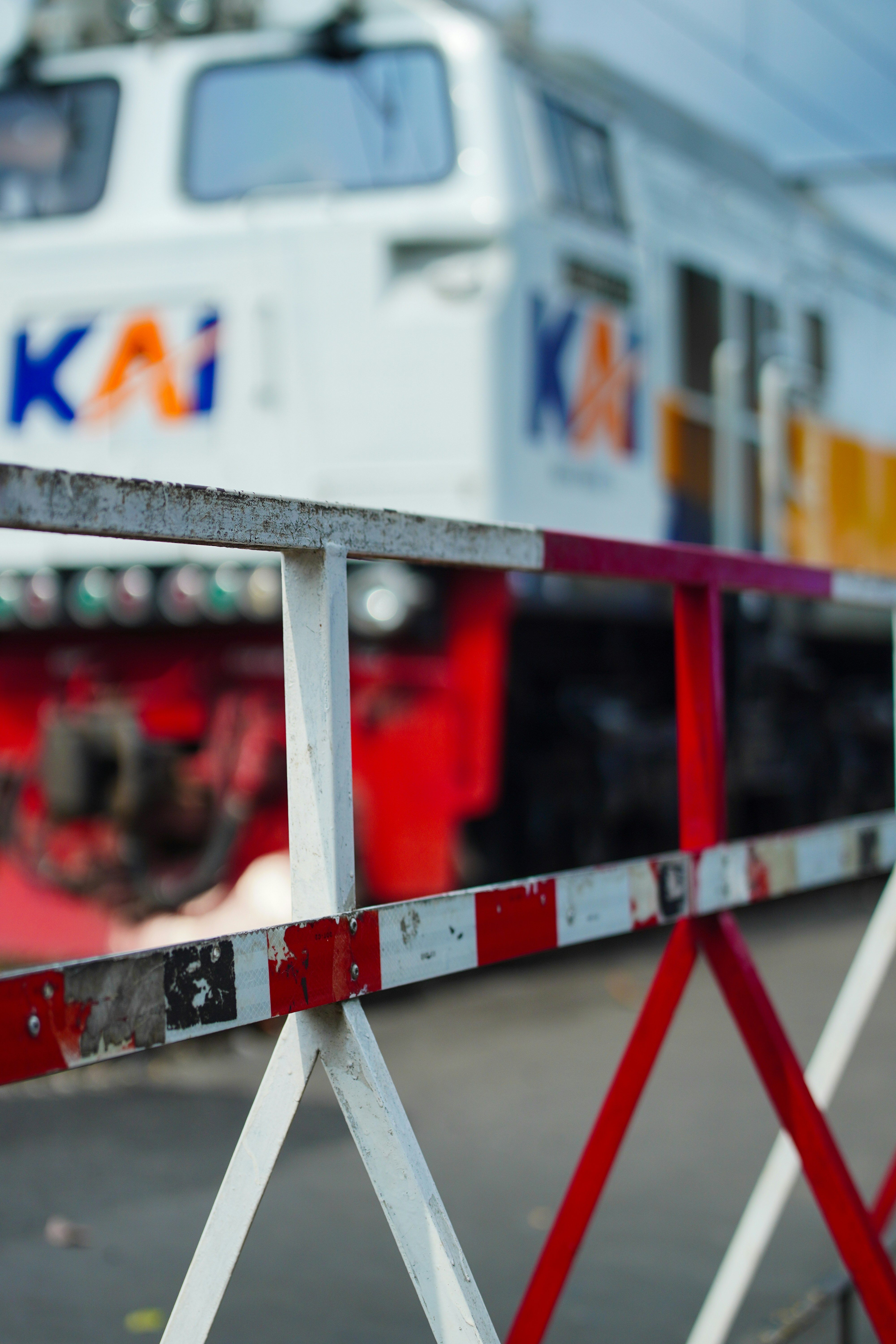 Red-and-white Barrier Frame with Industrial Train in the Background