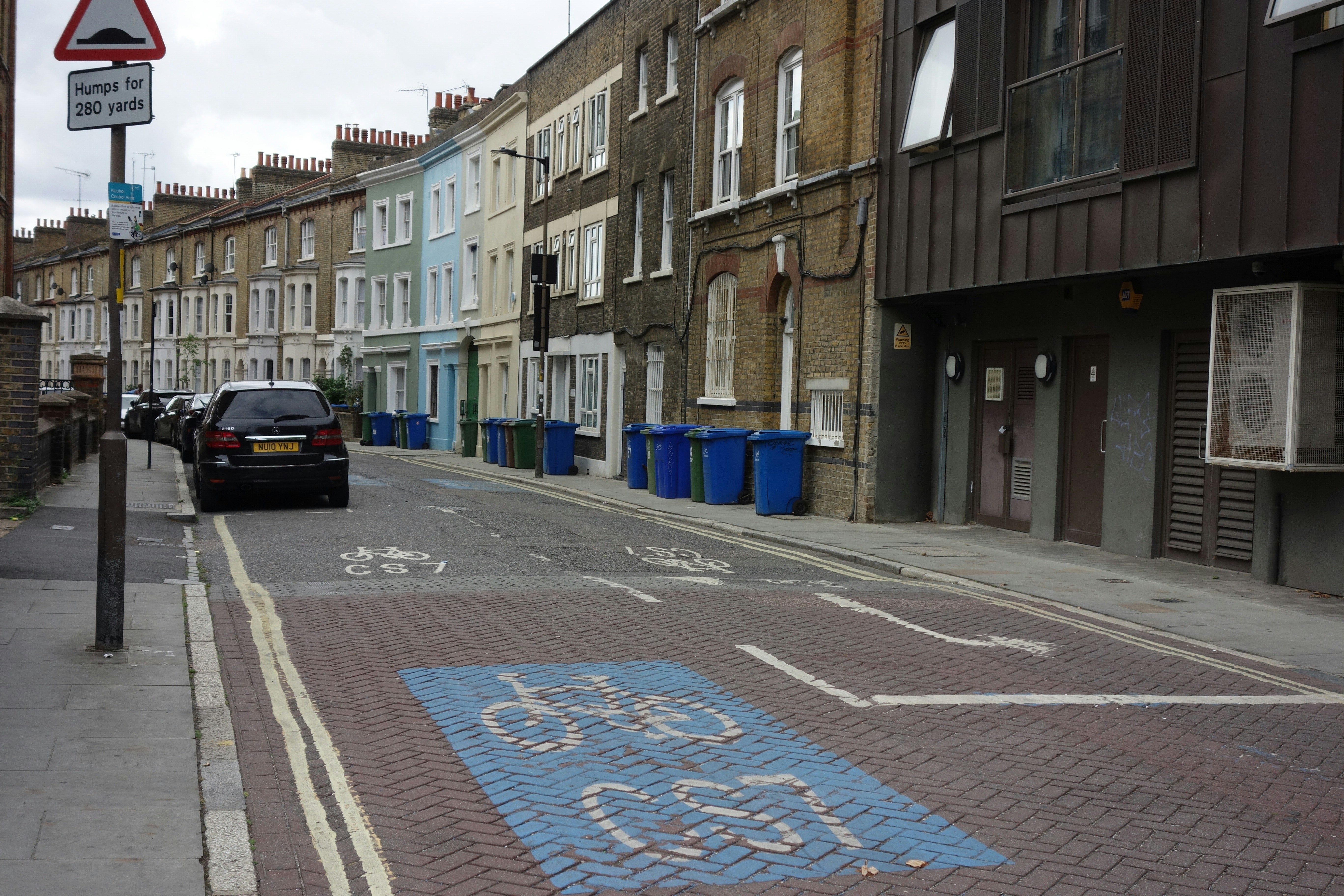 Blue Bike Lane Guiding the Street Through a Row of Colorful Townhouses