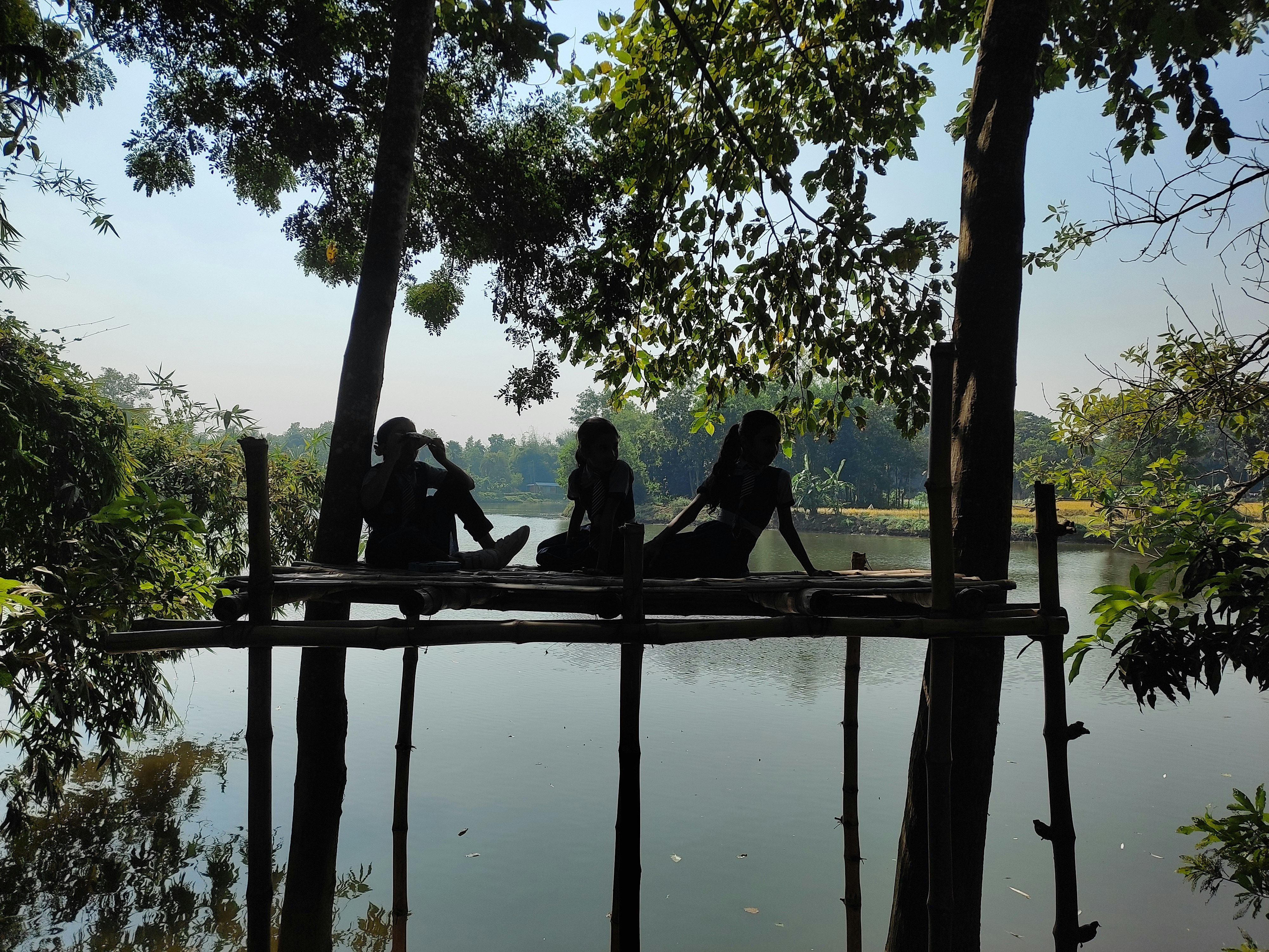 Silhouetted Friends on a Rustic Platform Over a Calm River