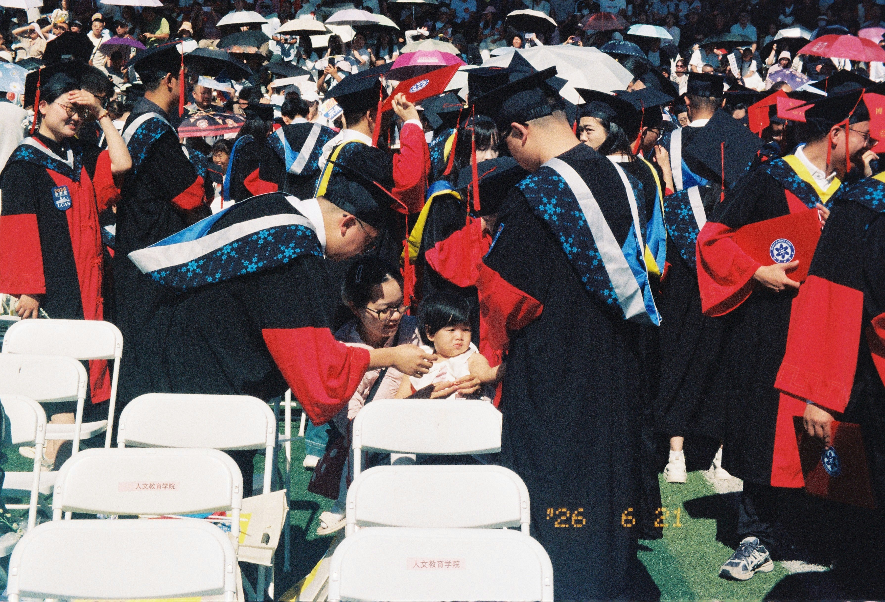 Ritual of Graduation: A Baby Seated Among Robes and Caps