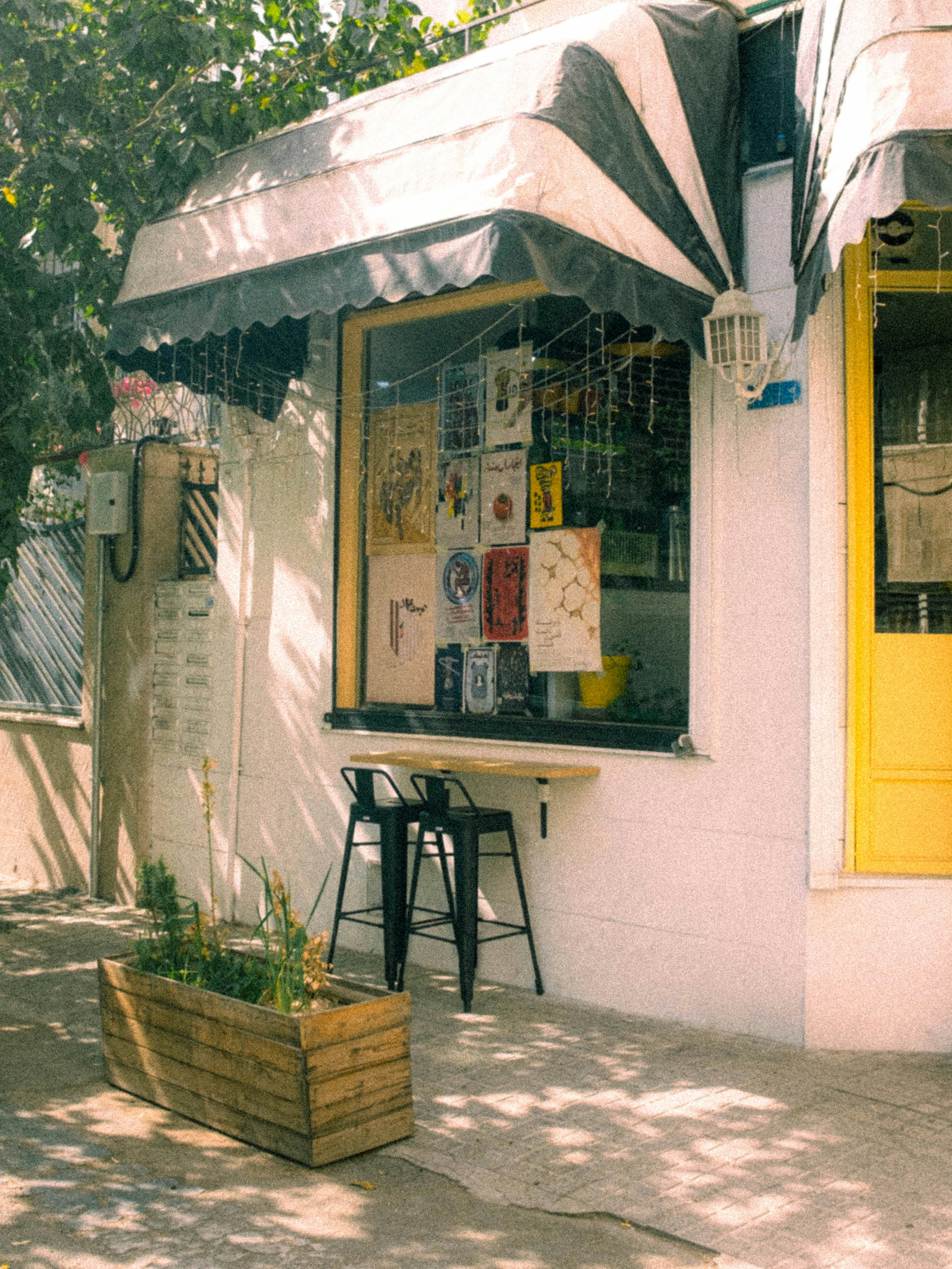 Sunlit Café Window: A Quiet Streetfront with a Bright Yellow Door