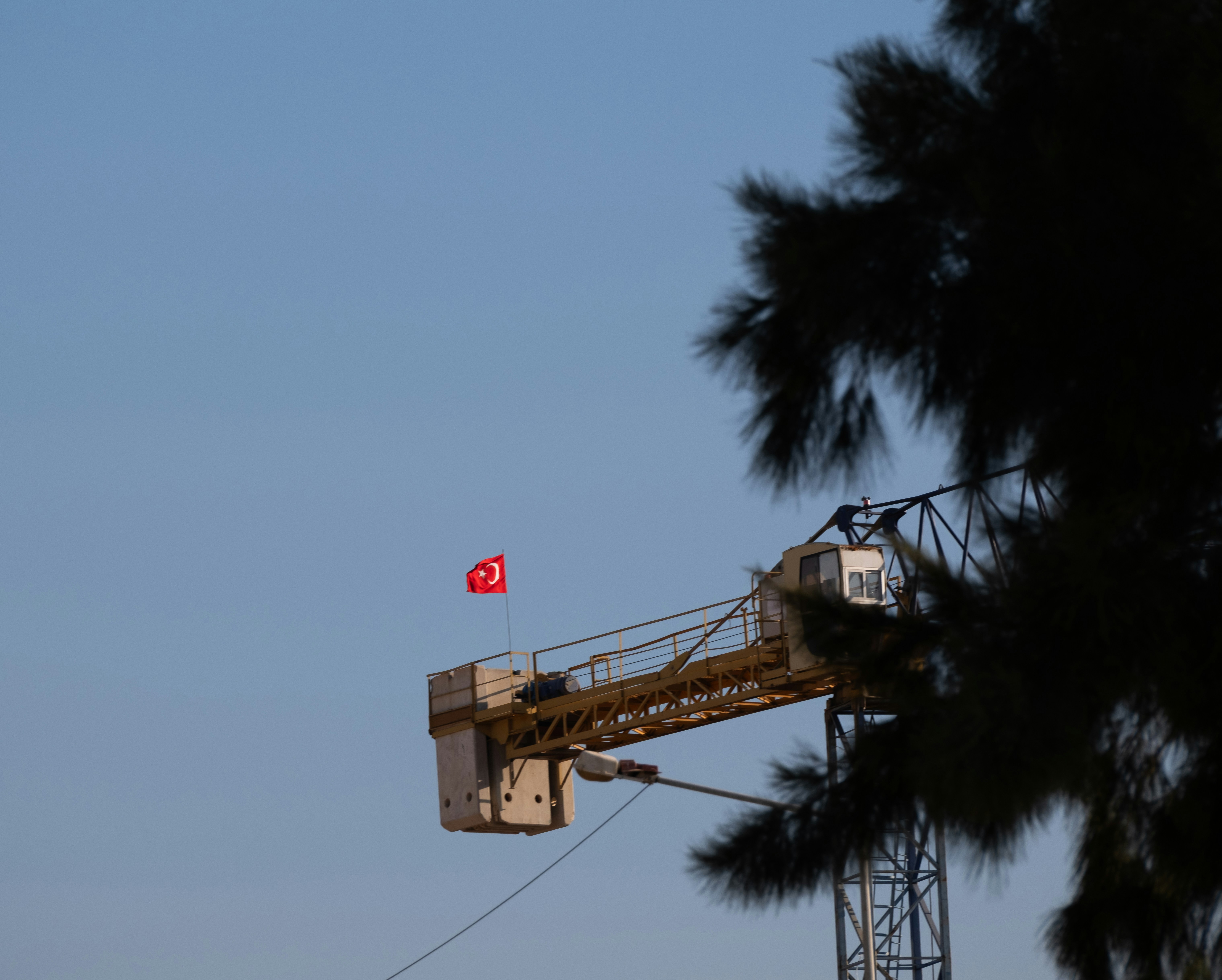 Turkish Flag atop a Construction Crane Against Clear Sky