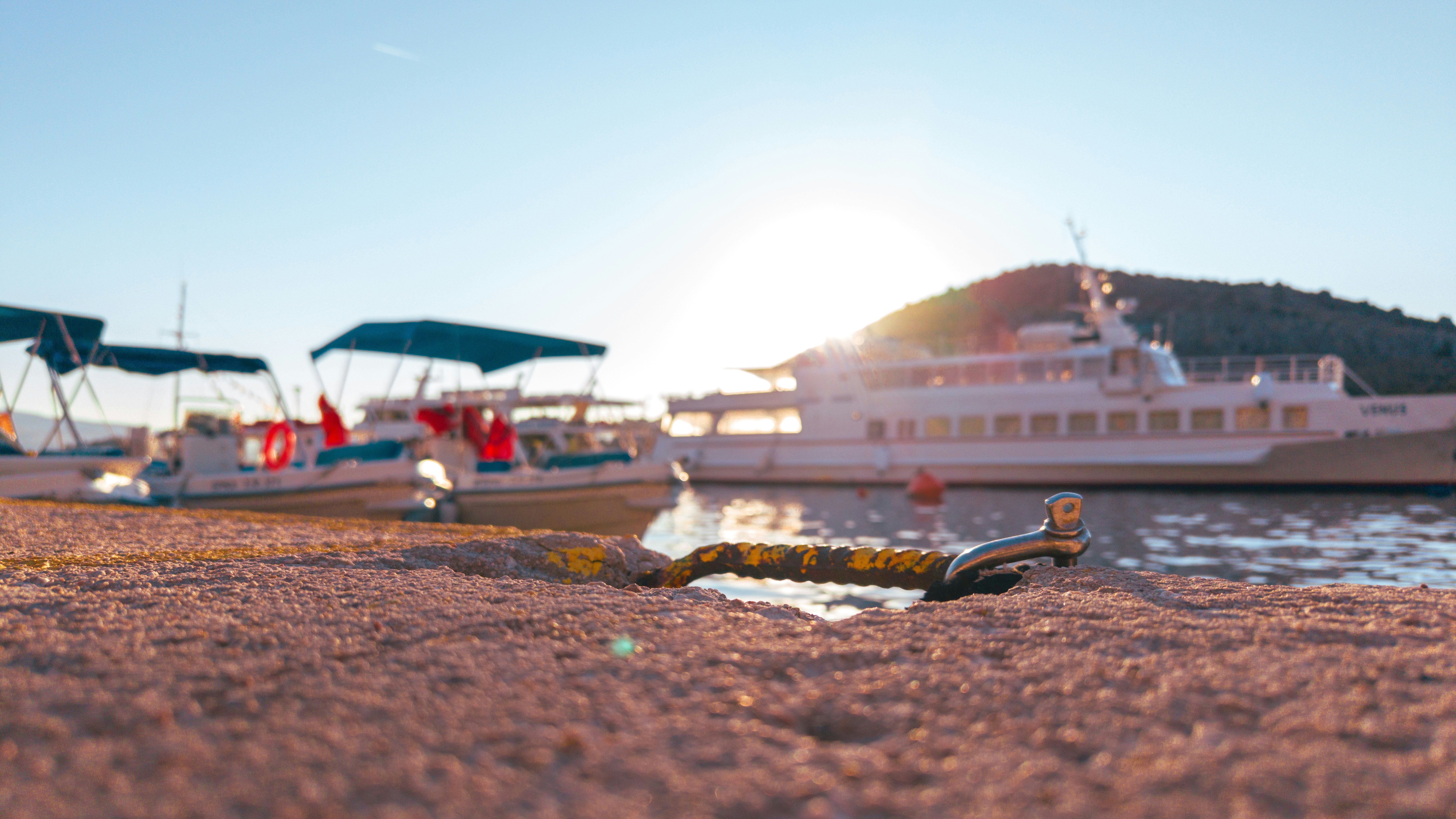Rusted anchor by sunlit marina: foreground detail meets distant boats