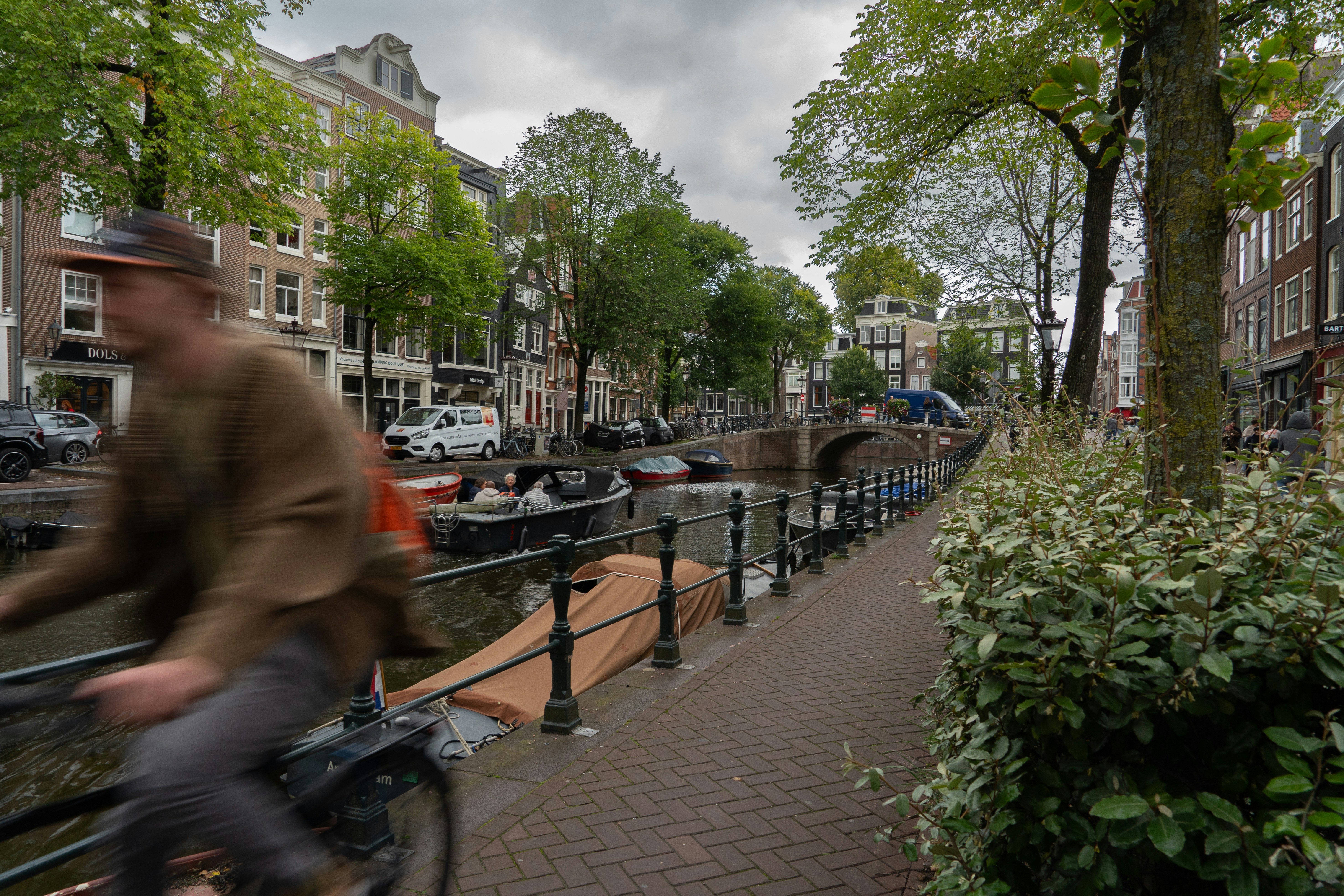 Bicyclist in motion along a sunlit Amsterdam-style canal path