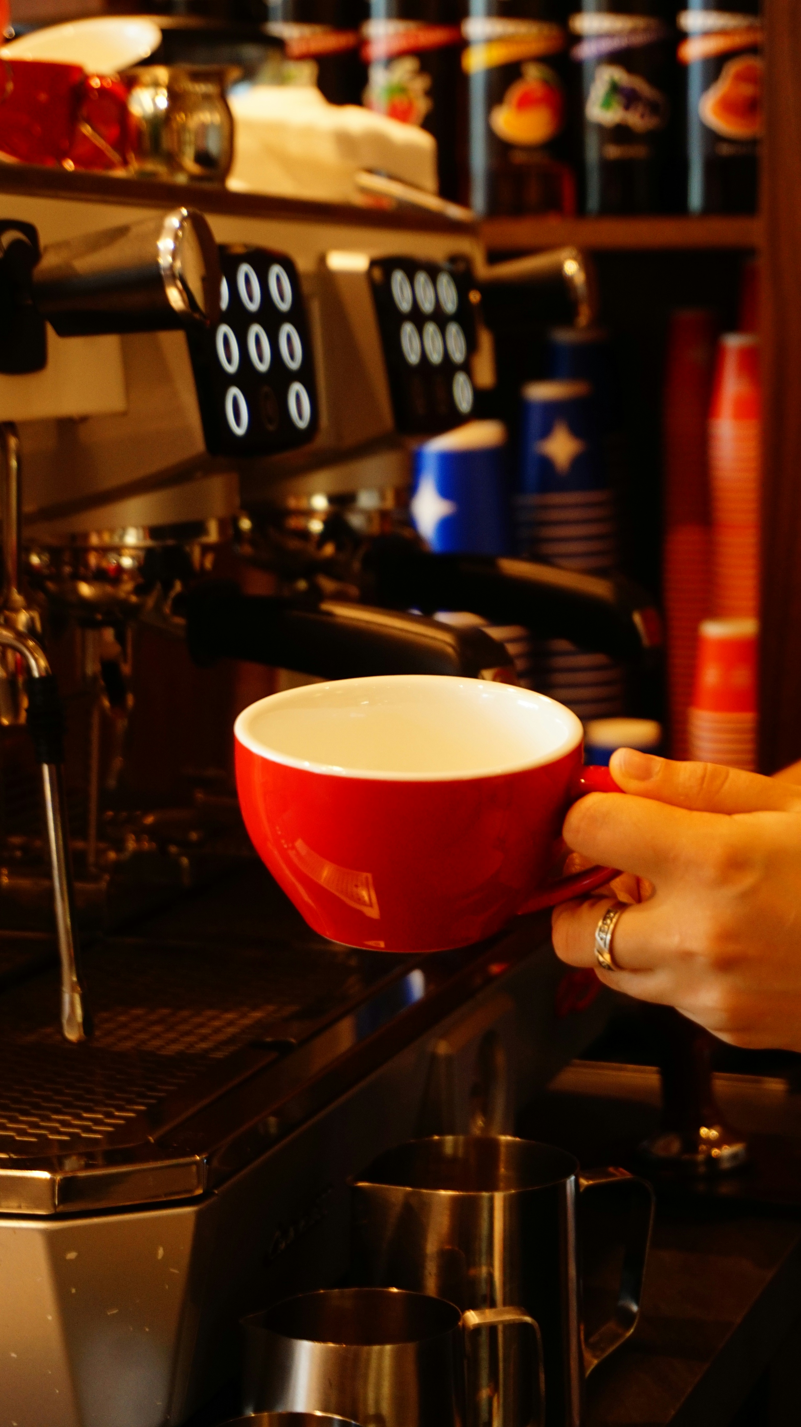 Red Cup in Focus: A Barista’s Hand Reaches for Warmth
