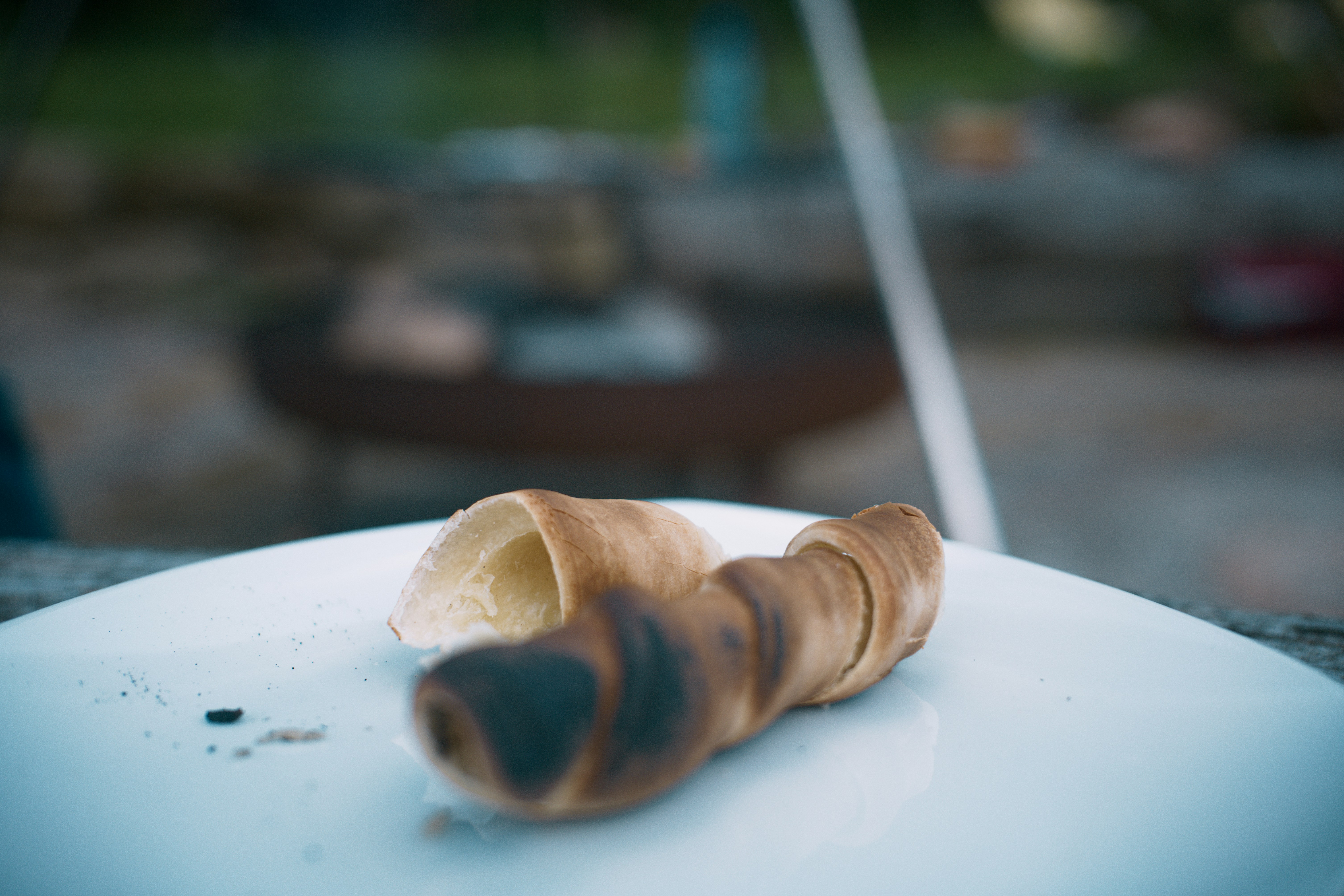 A toasted dough spiral on a white plate outdoors