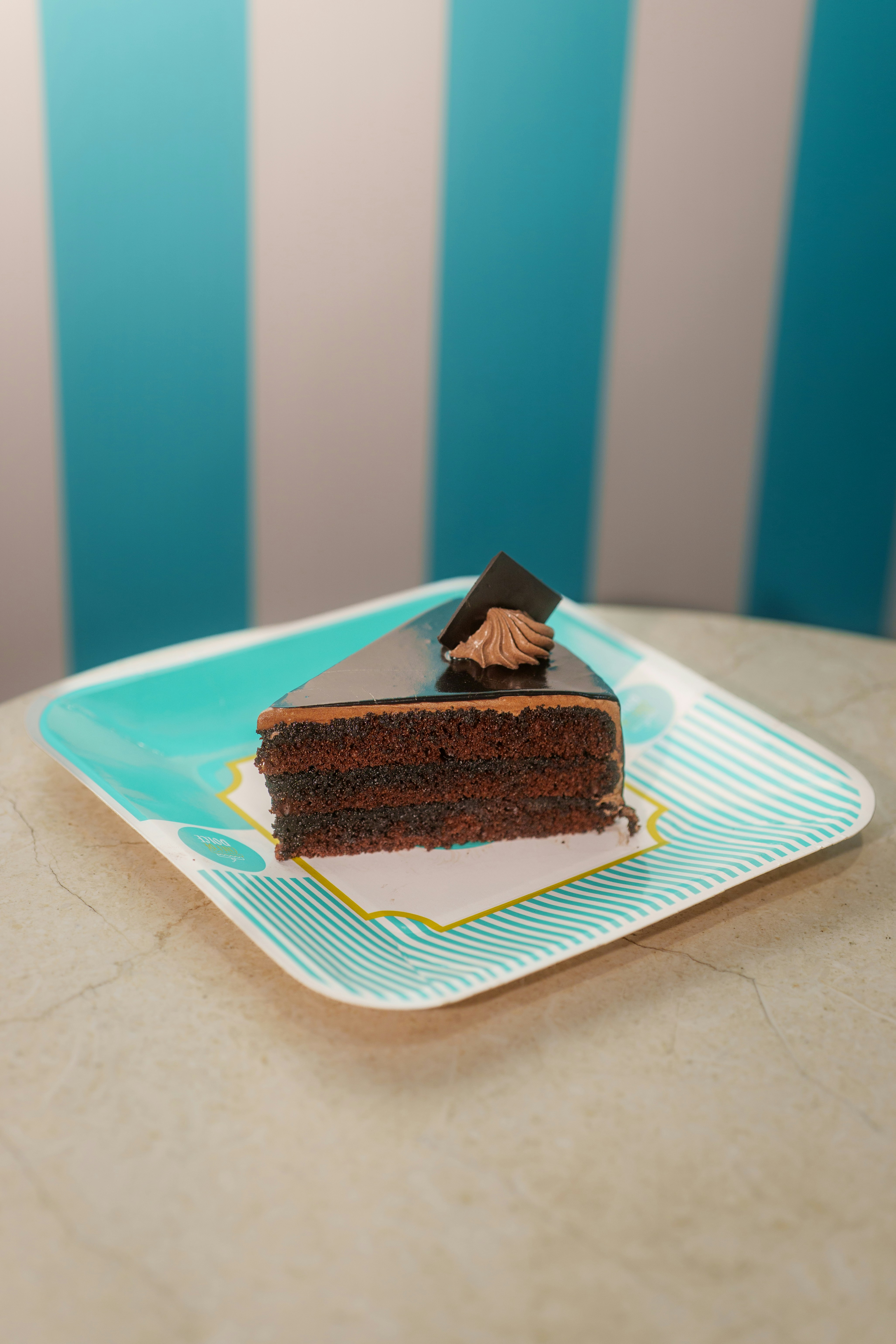A slice of layered chocolate cake on a turquoise patterned plate