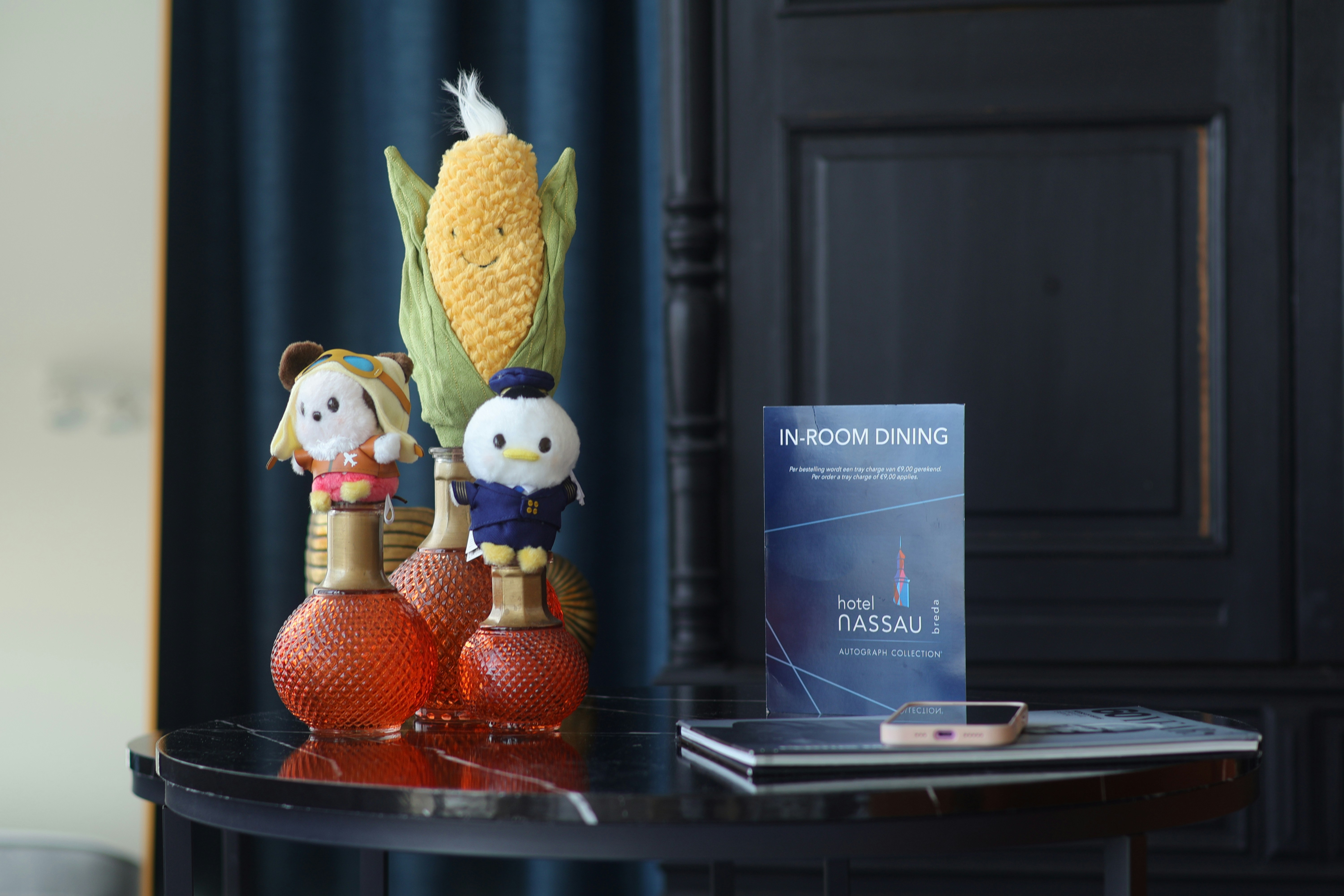 Plush toys perched on orange glass bottles beside an in-room dining menu