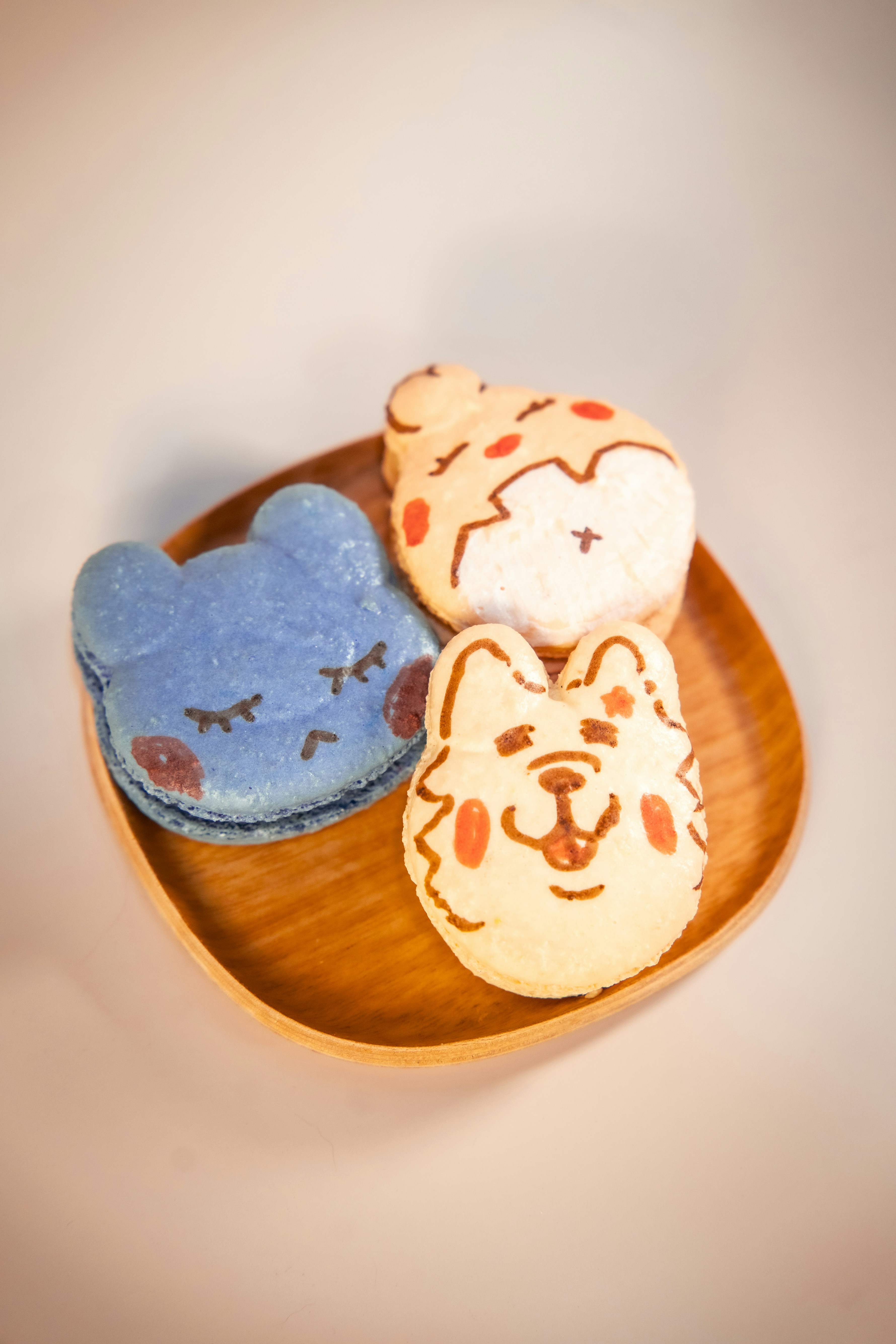 Three Character Cookies: Blue Bear, Sleeping Cat, and Smiling Dog on a Wooden Plate