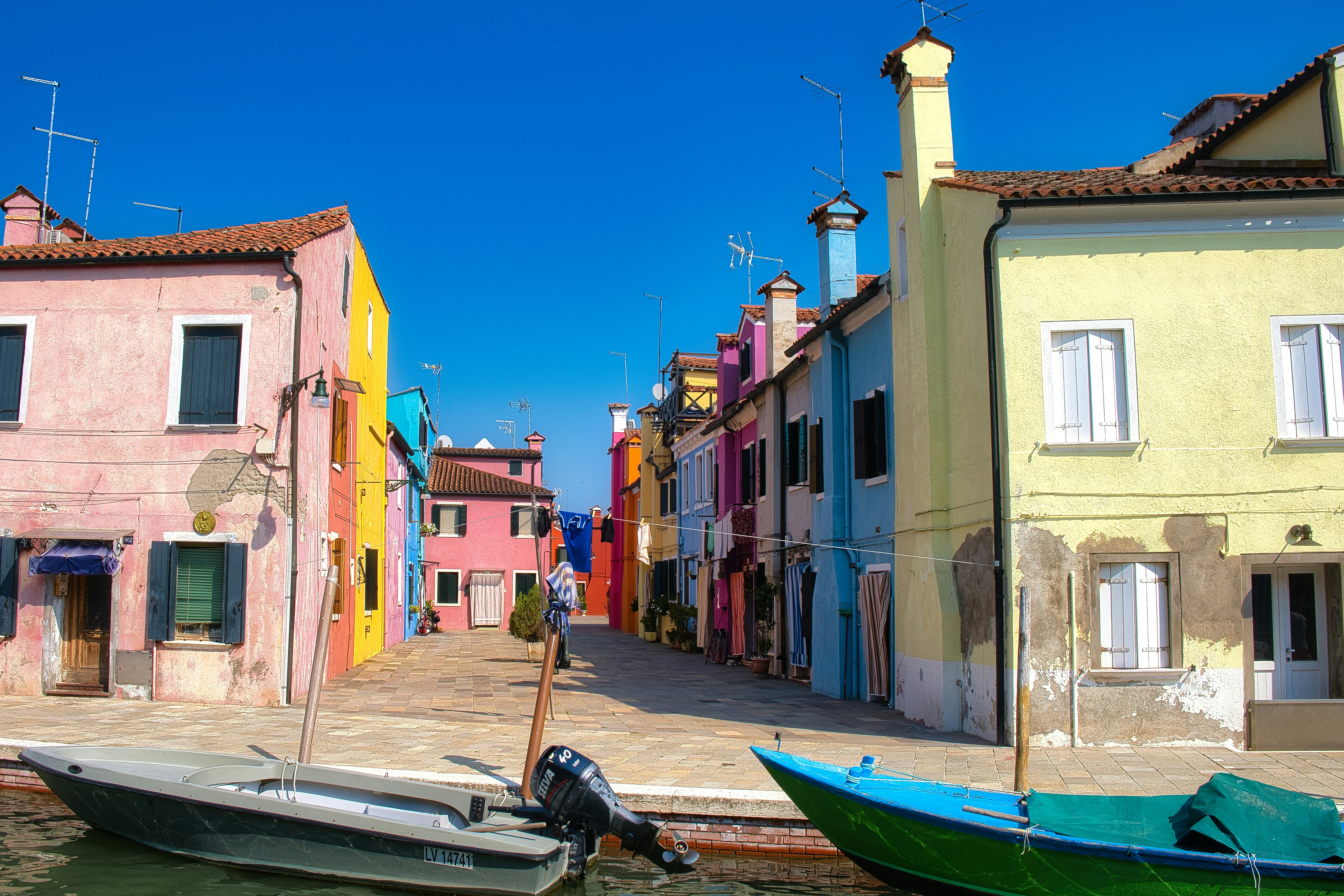 Colorful waterfront alley in Burano with boats at the canal edge