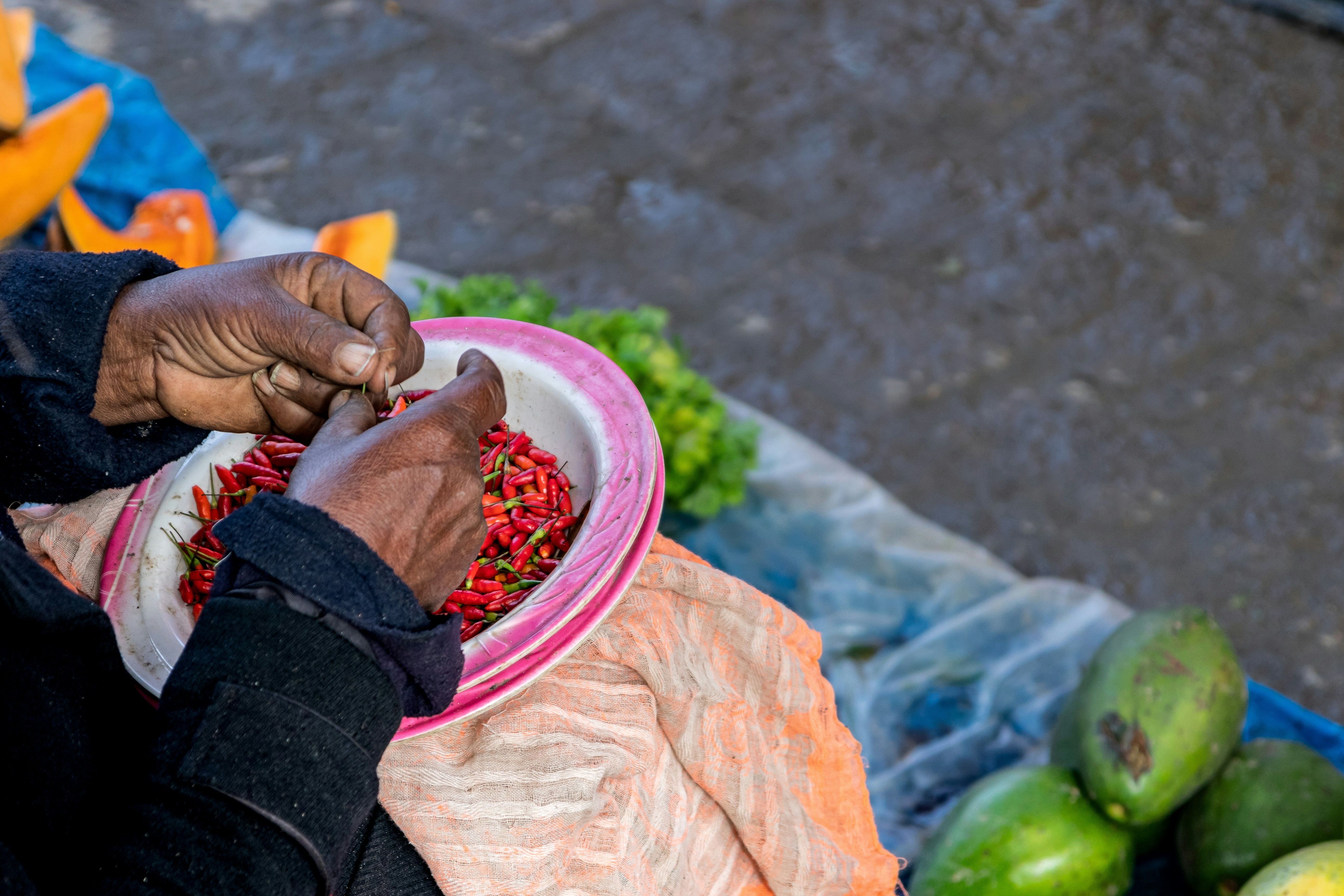 Hands at Work: Red Pepper Grains Near a Woven Cloth and Fresh Produce