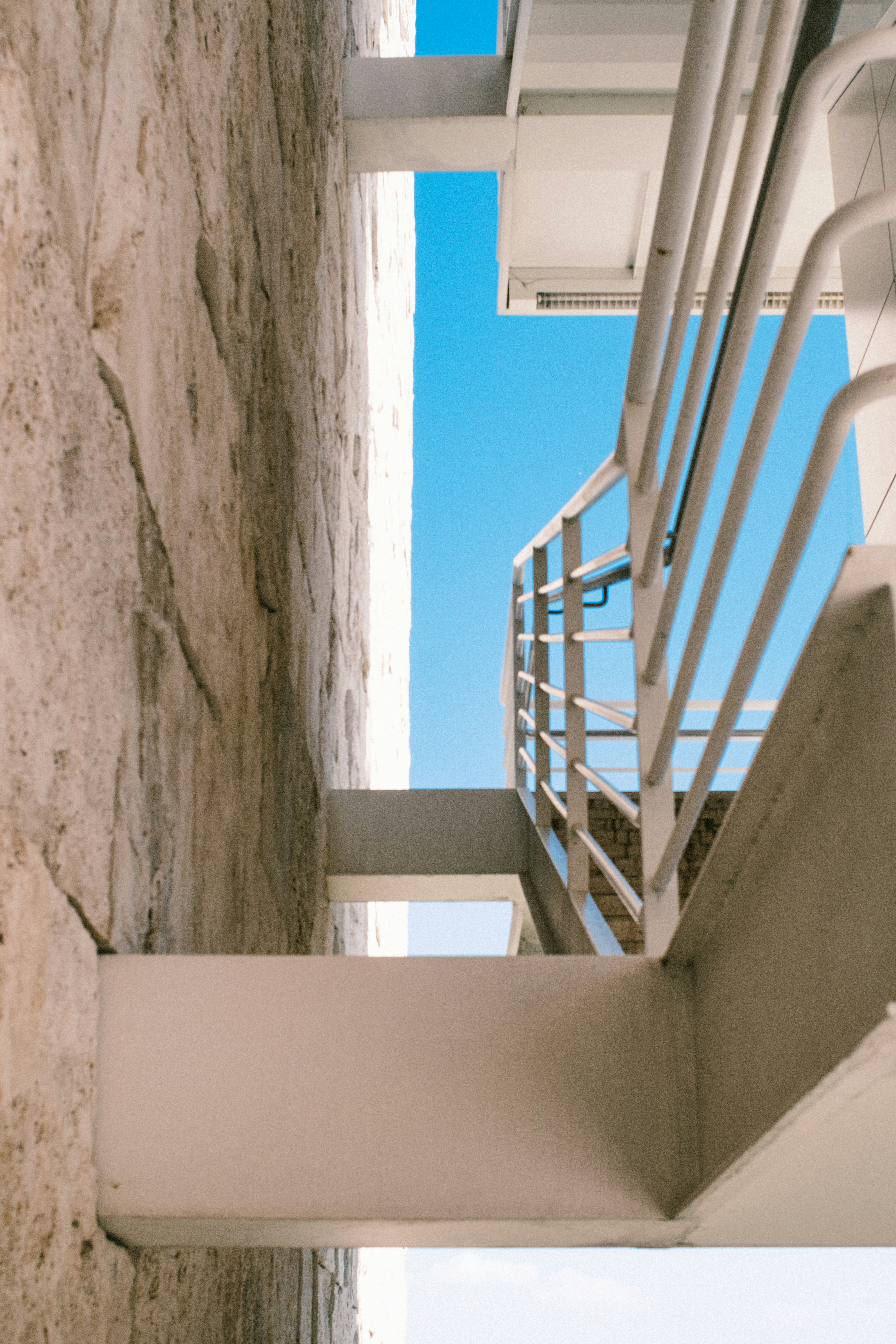 Skyward Gap: Concrete Walkway Framed by Railings Against a Crisp Blue Sky