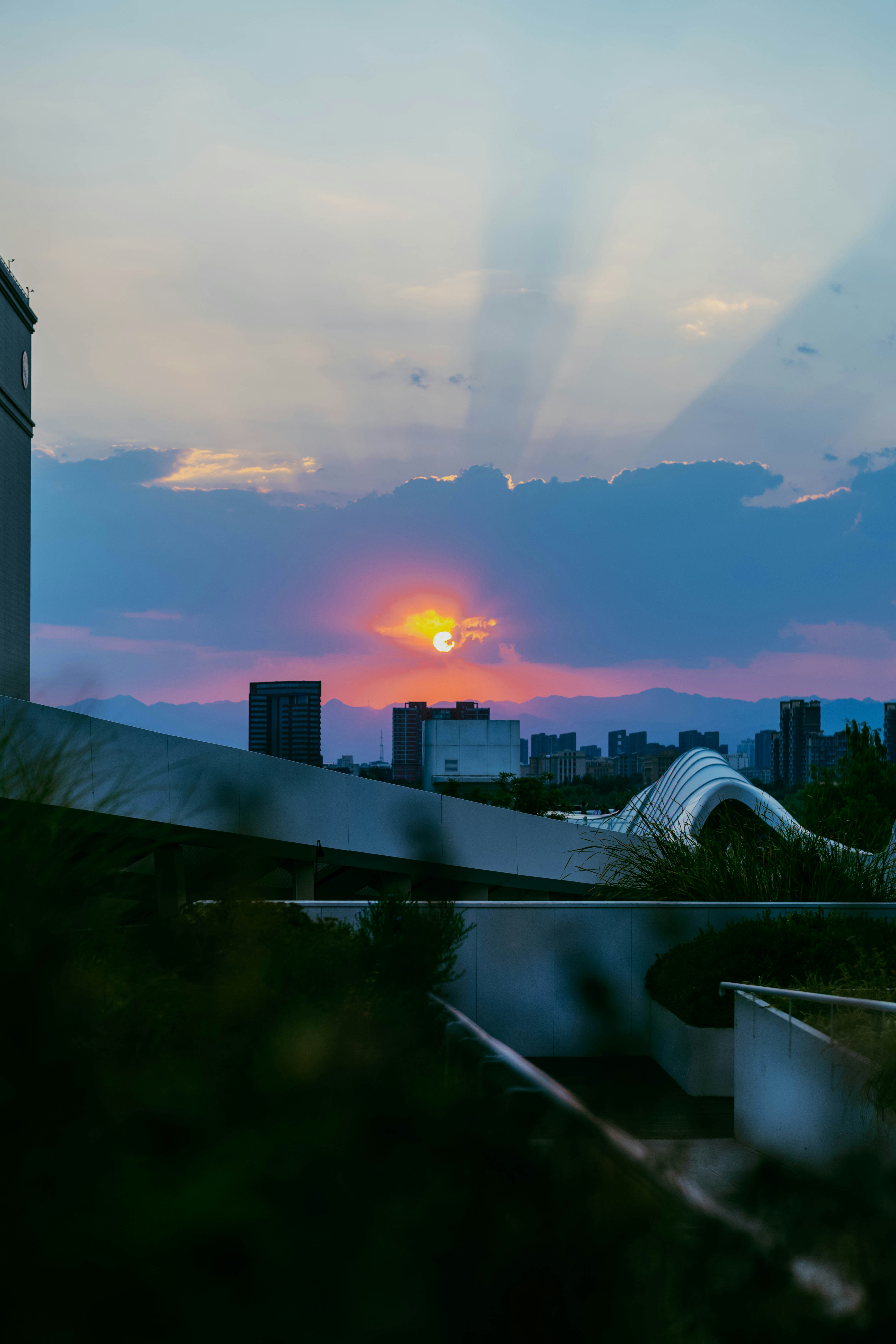 Sunset Over City Lines: Rays Cut Through a Modern Rooftop Scene