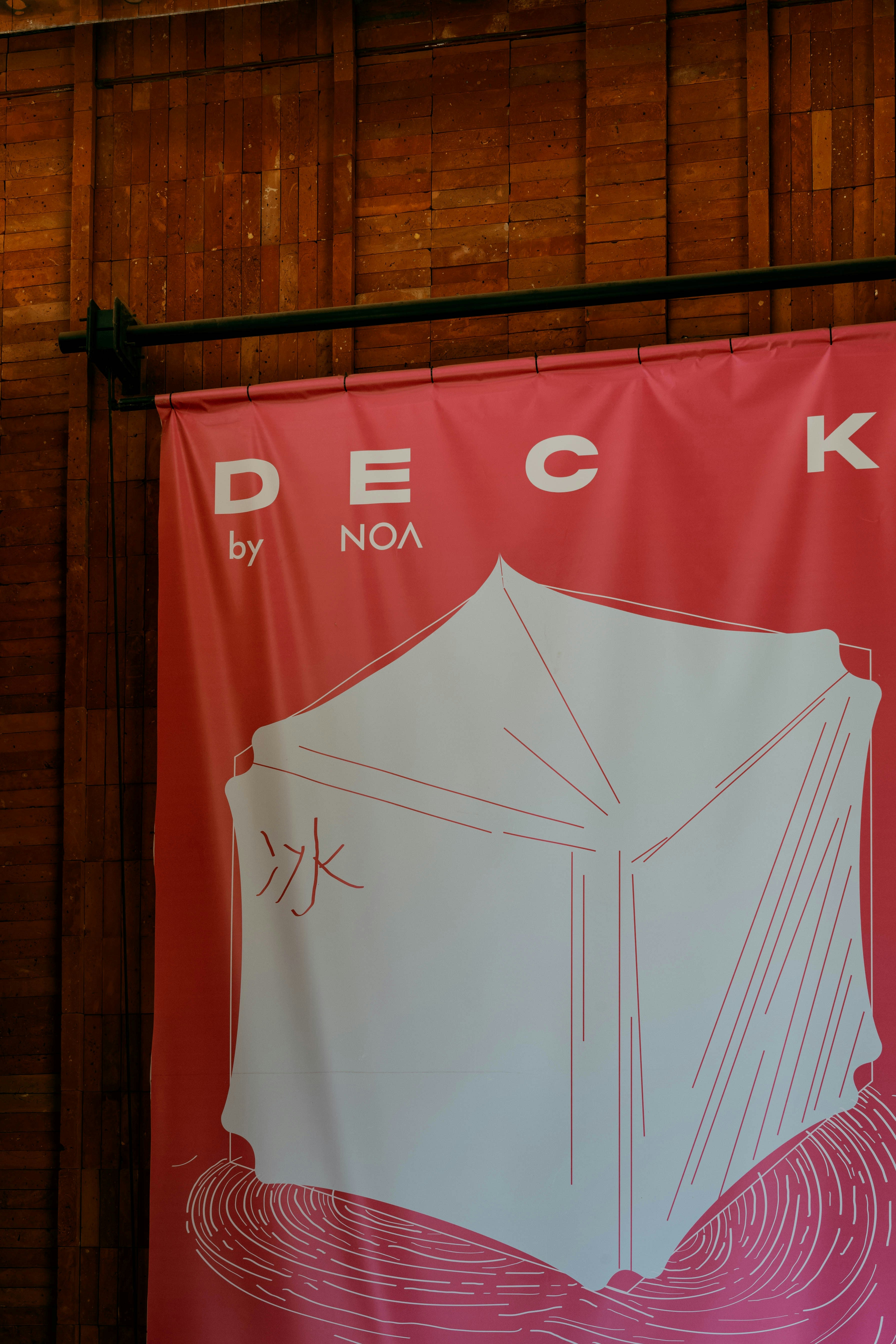 Bright red banner with a white geometric ice shard design hangs against a dark wooden wall, suggesting a stall or exhibit setup.