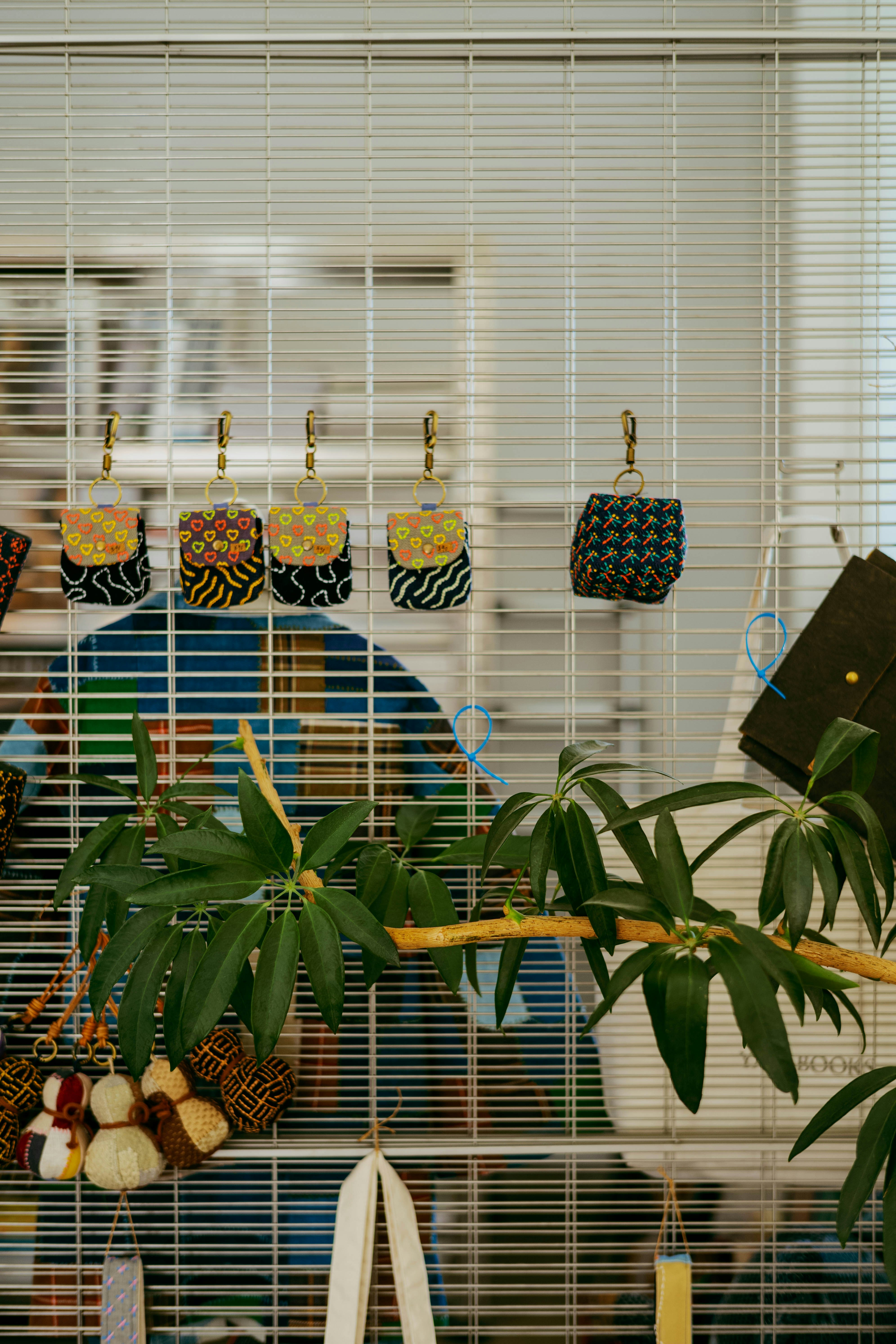 Colorful charms on a grid: a shop window of woven pouches and leafy greens