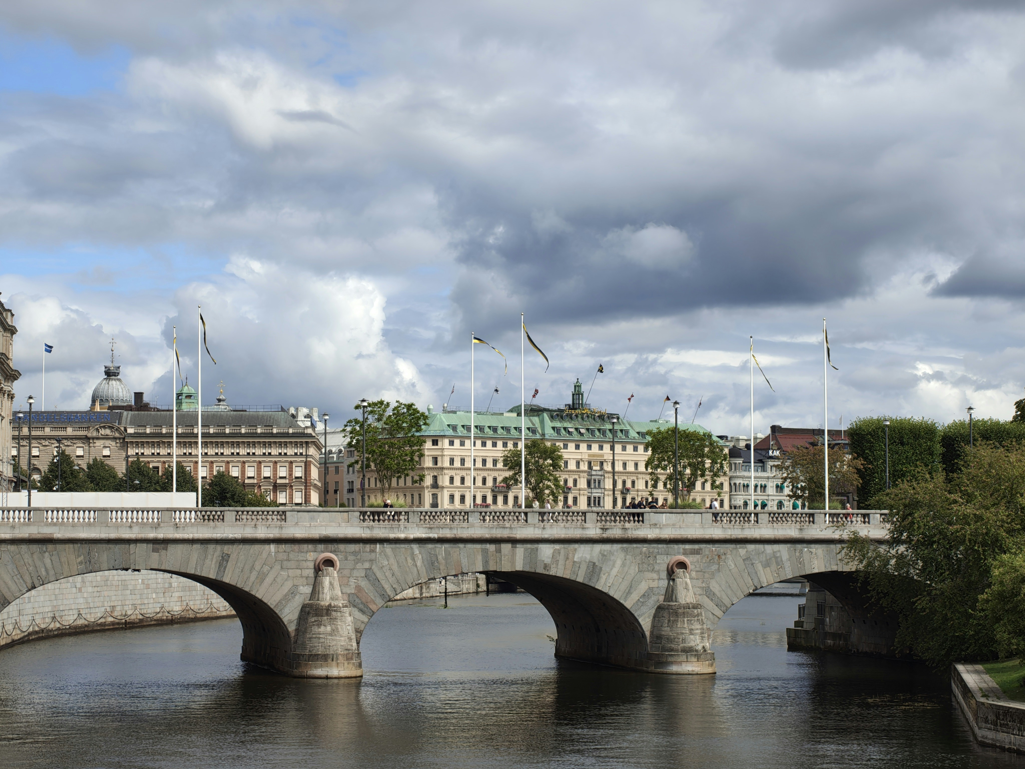 A stone arch bridge over a river in Stockholm with historic buildings behind