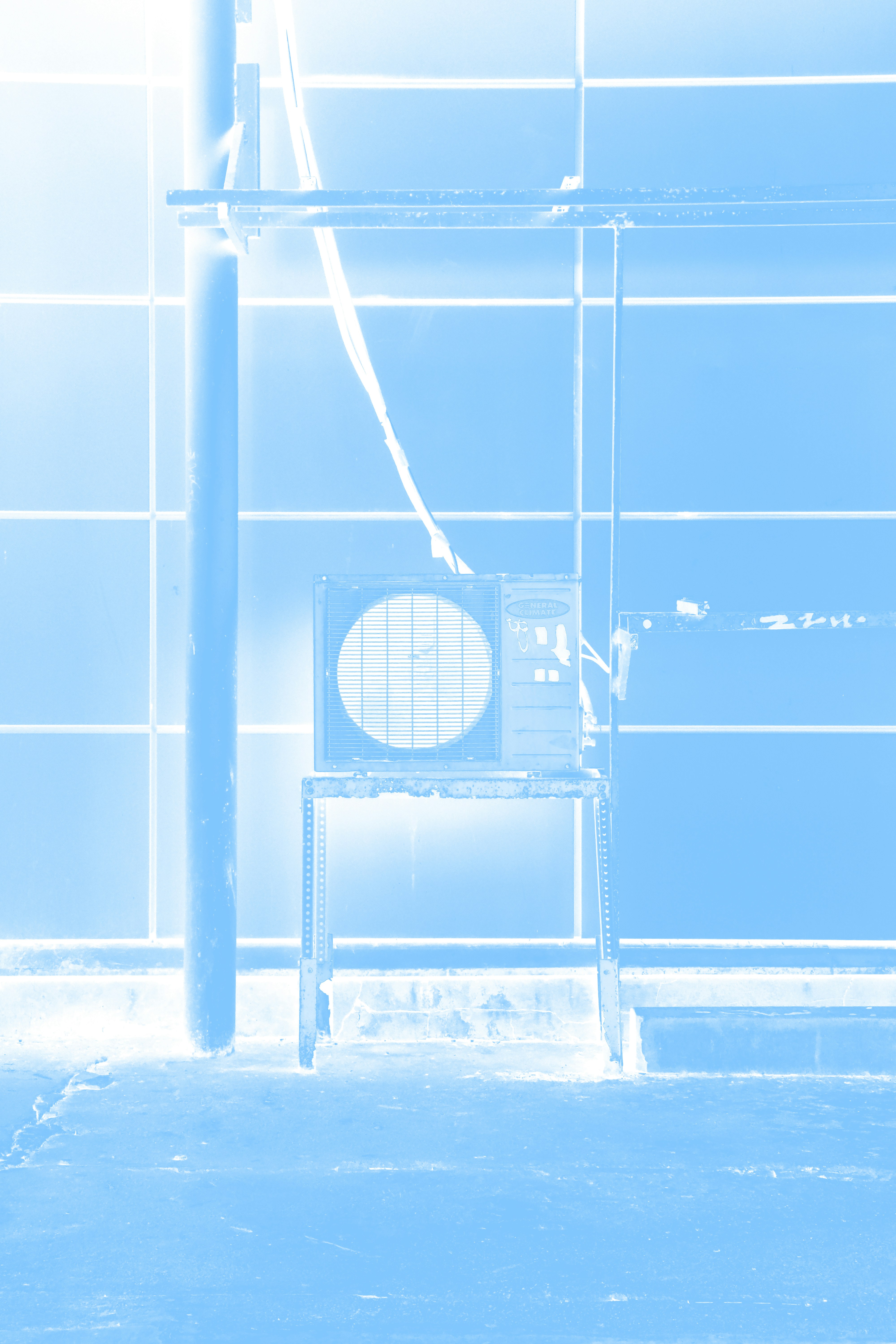 Blue-tinted rooftop HVAC unit against a geometric wall of windows, emphasizing industrial lines and minimal color. This is a photographic capture with architectural elements dominating the frame.