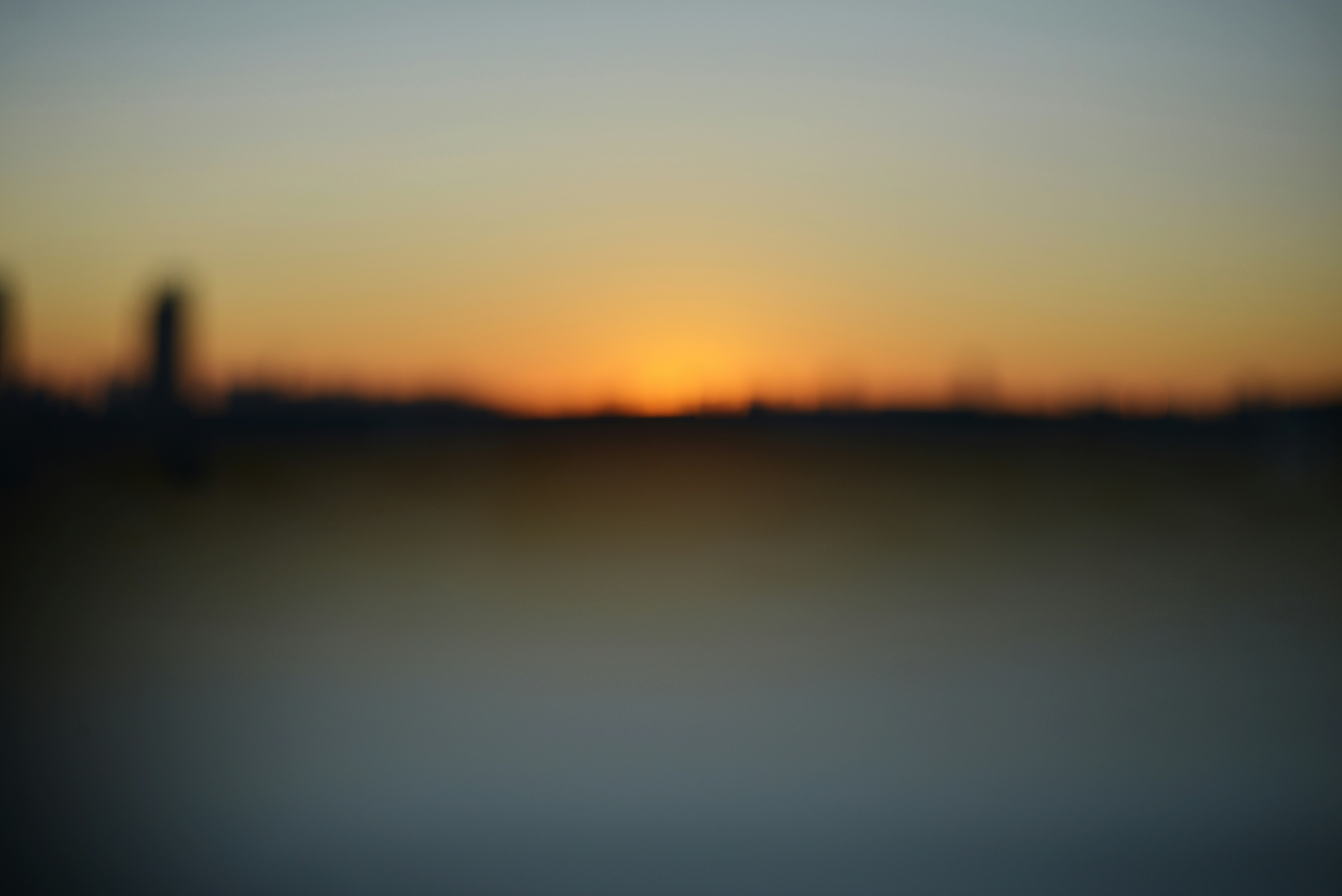 Horizon Blur: A Quiet Sunset Across a Distant City Ridge