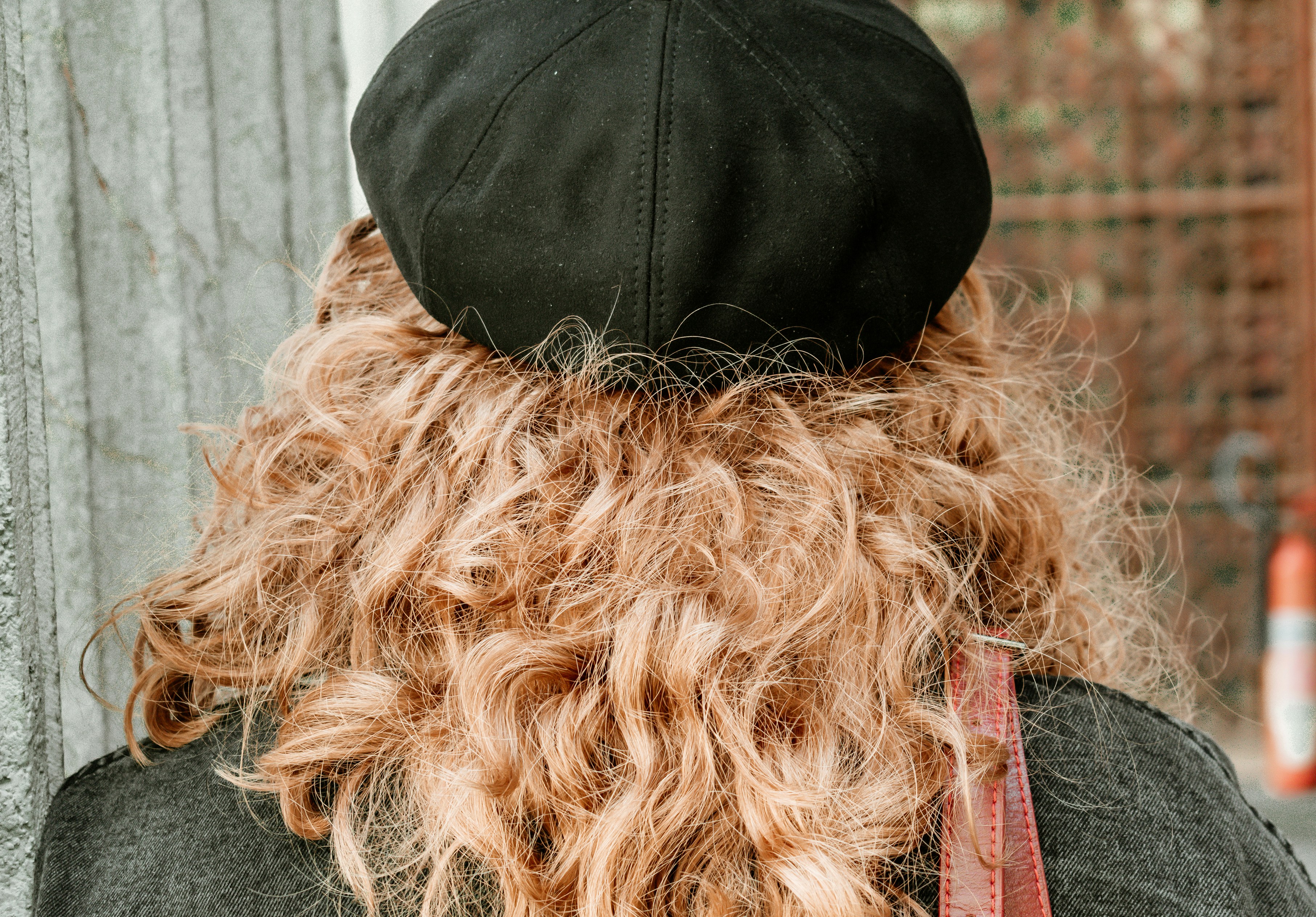 A person with curly ginger hair wearing a black beret and dark jacket