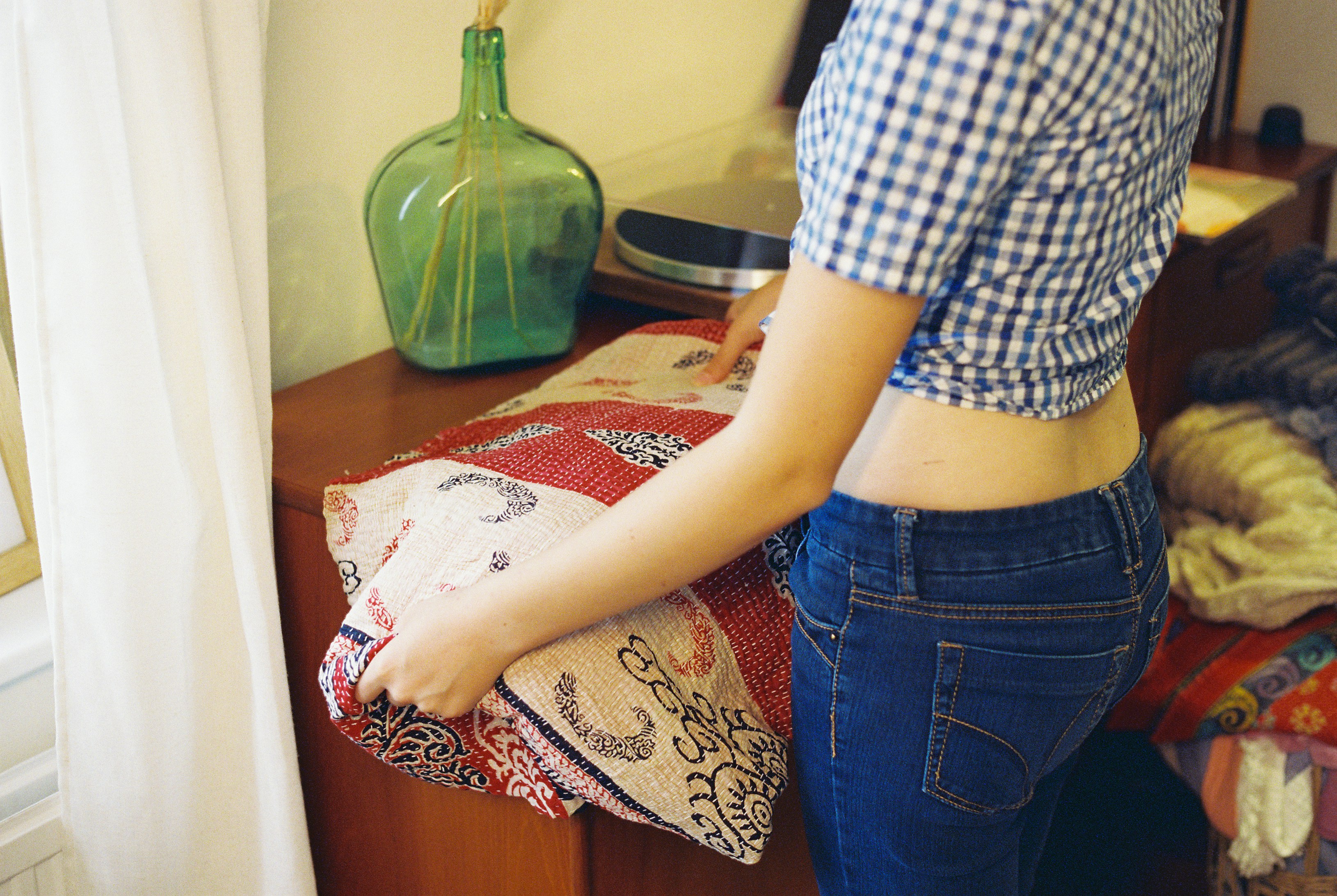 Tailored Comfort: A Person Arranges a Quilt on a Dresser
