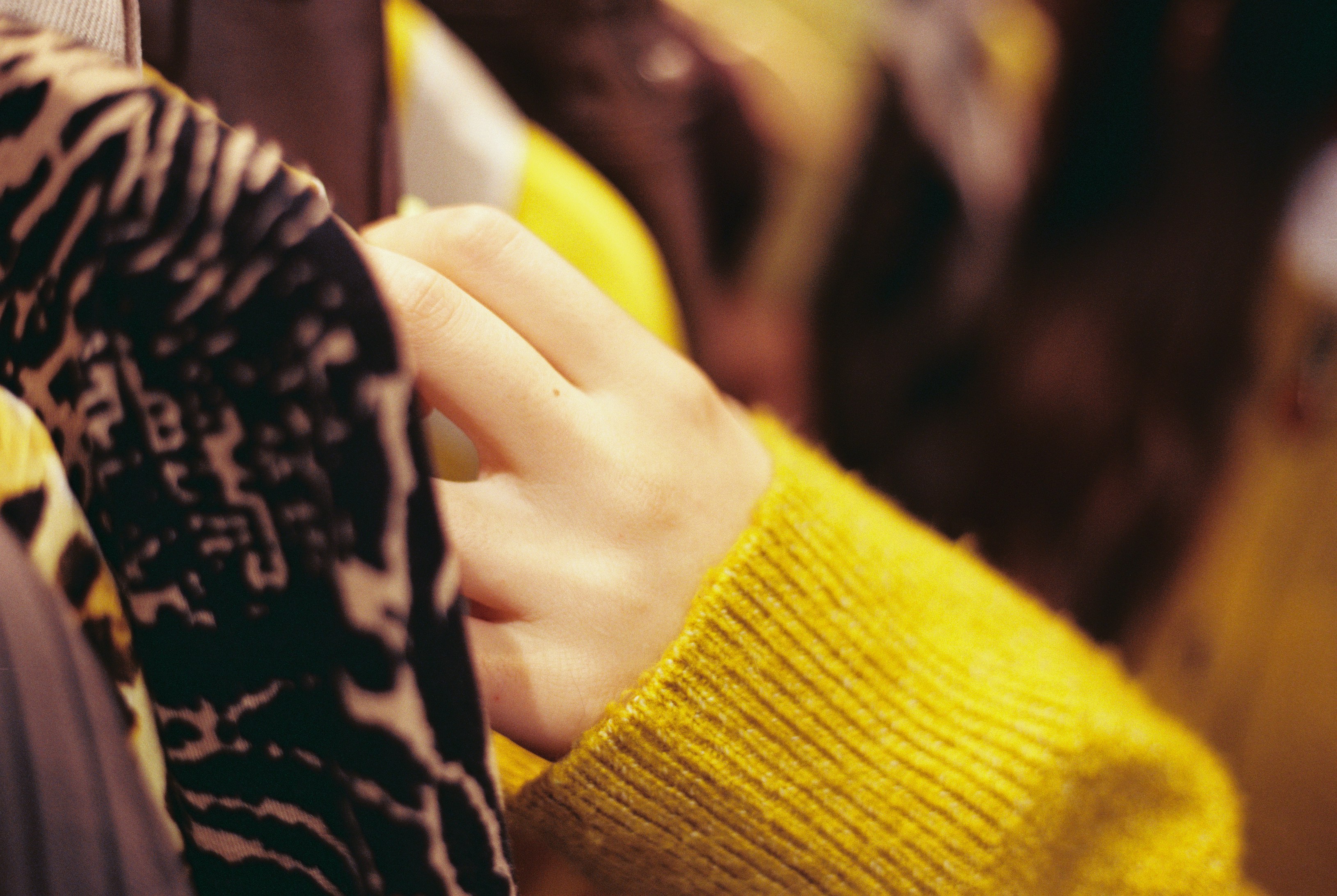 Yellow Knit Grip: A Hand with Patterned Fabric Touches Fabric Edge