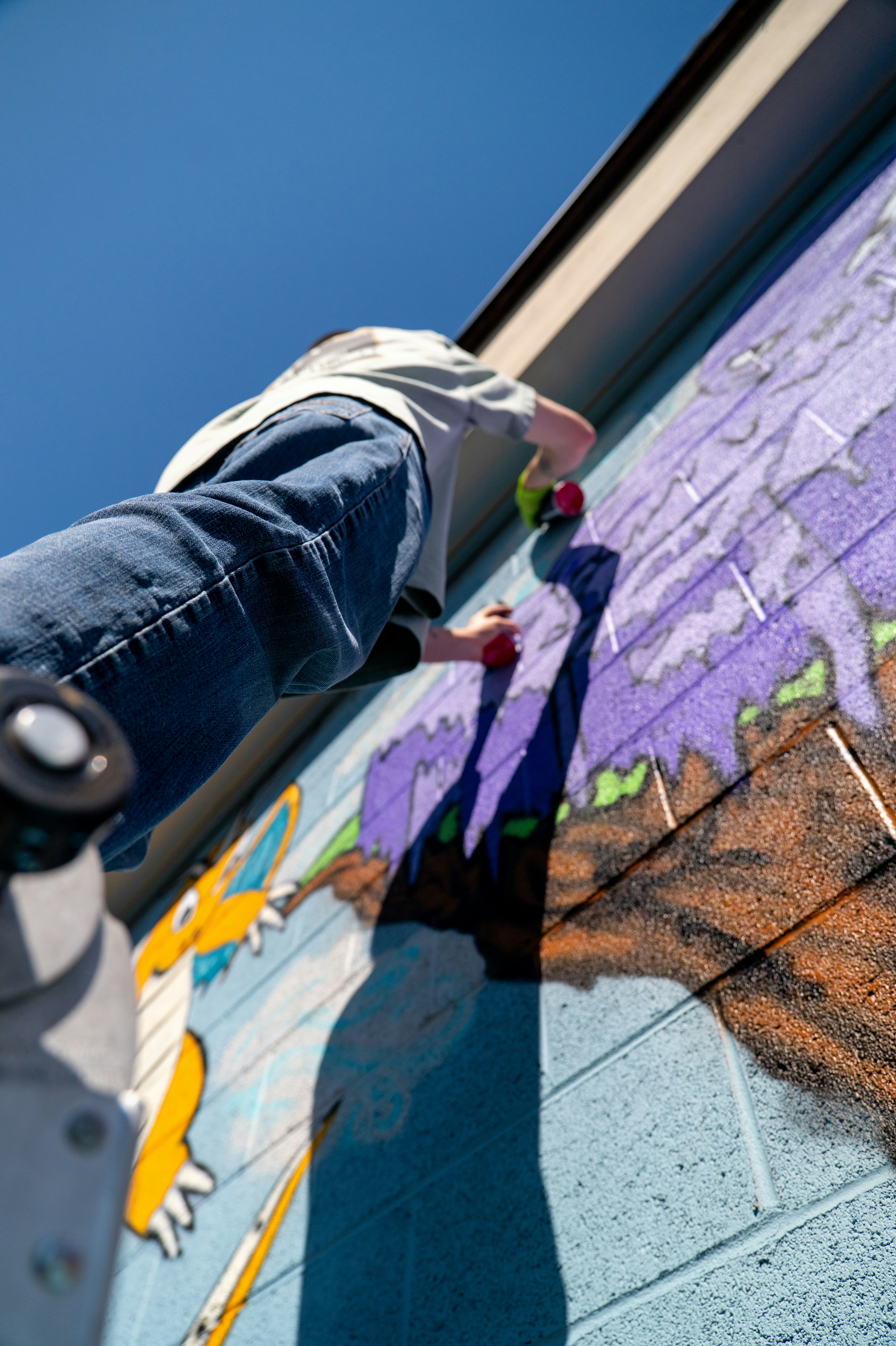Climbing Graffiti: A Kid Painting a Colorful Wall from an Aerial Angle