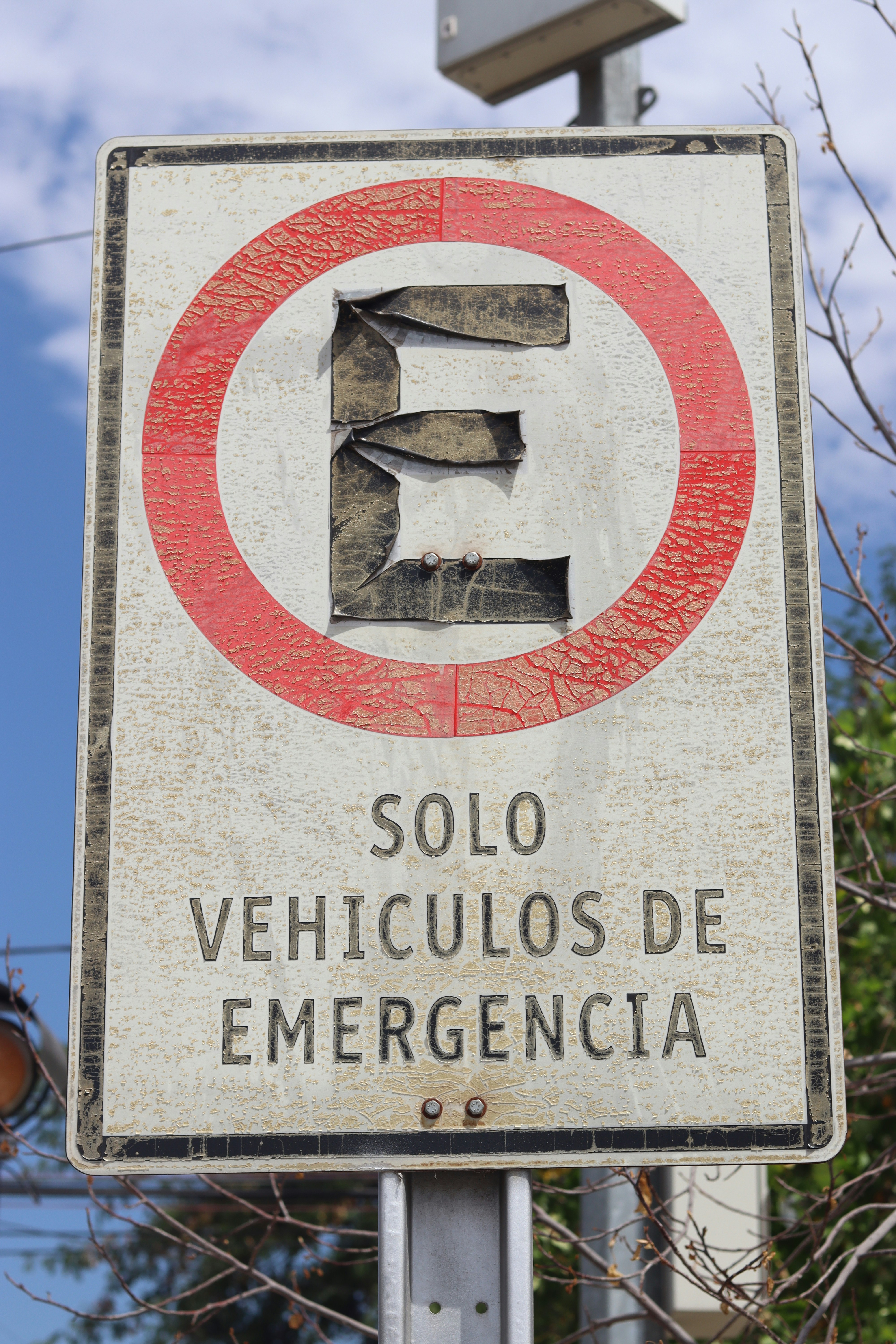 No Entry for Emergency Vehicles: Weathered Spanish Sign on a Metal Post