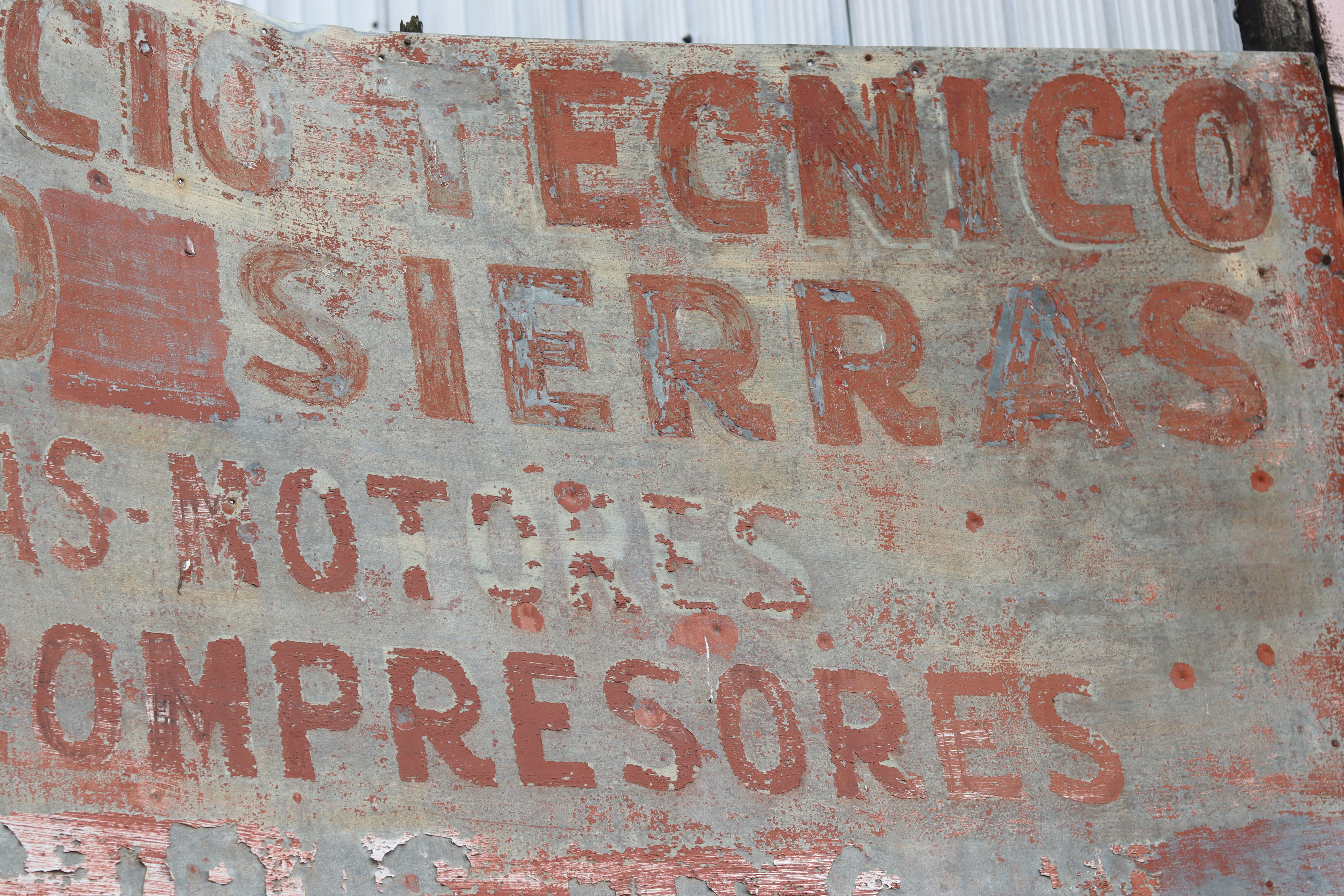 Weathered sign of technical signage in faded red letters