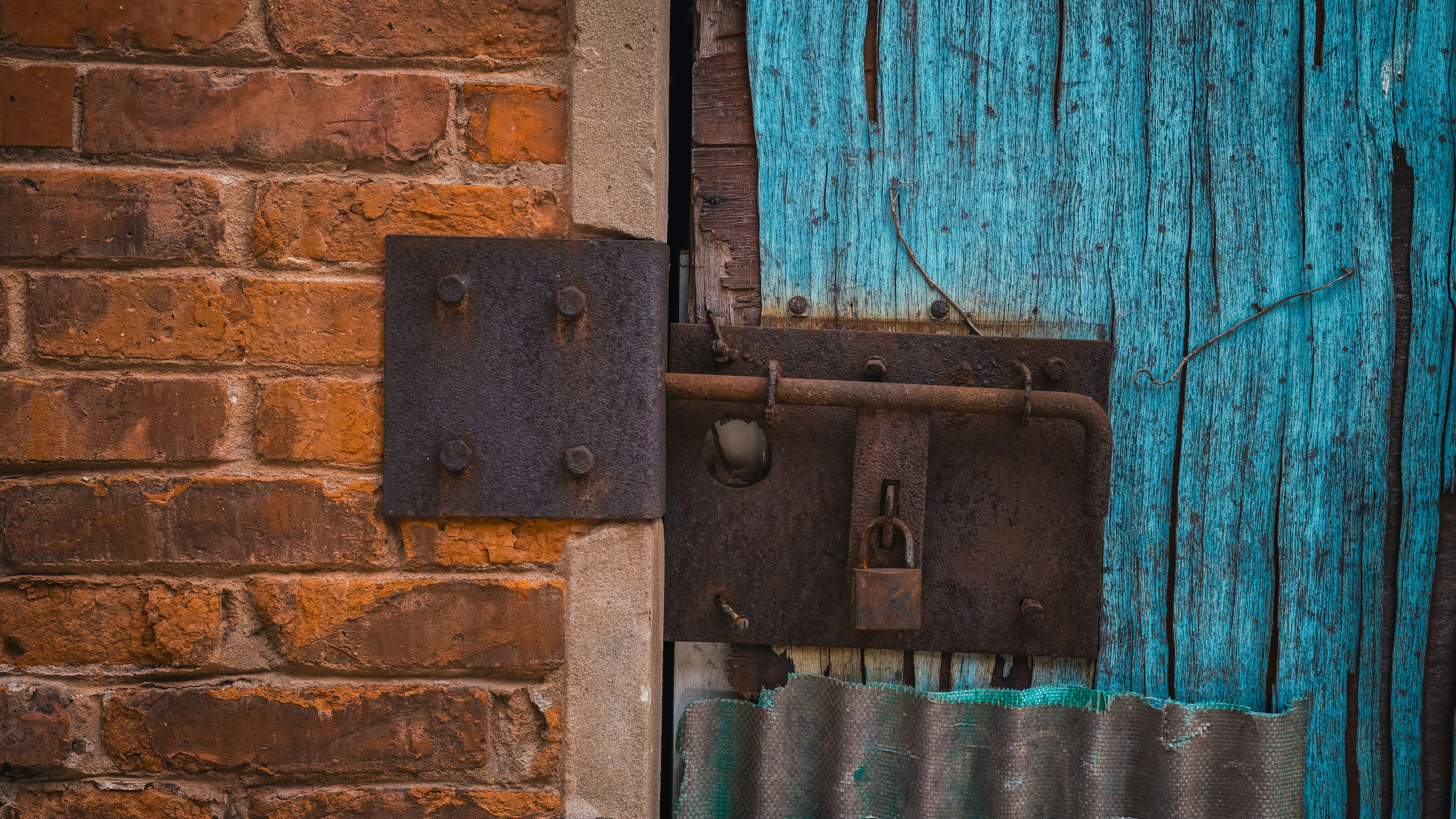 Weathered Doorway: A Quiet Clash of Brick and Turquoise Wood