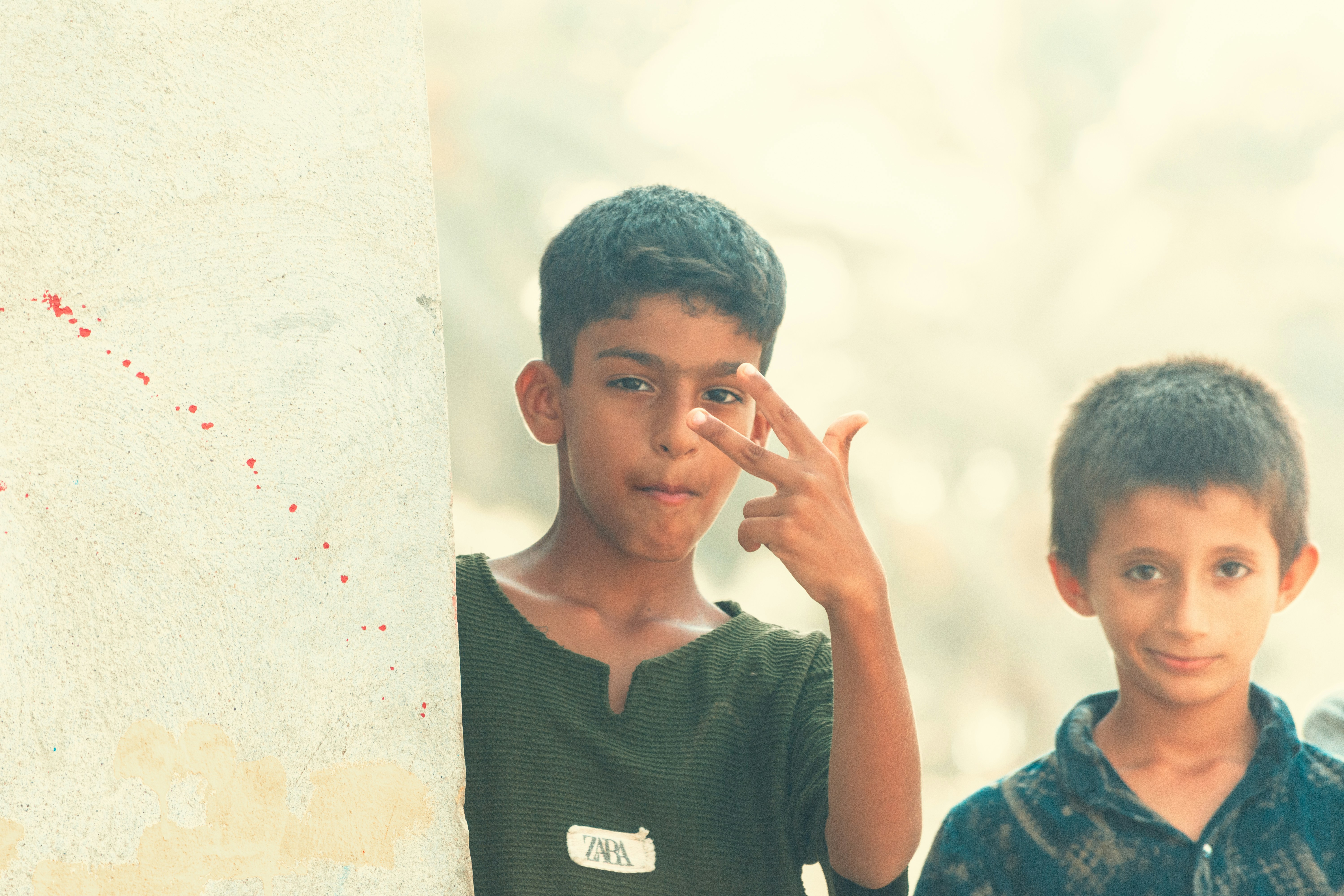 Two brothers at the edge of light, a candid gesture under warm shade
