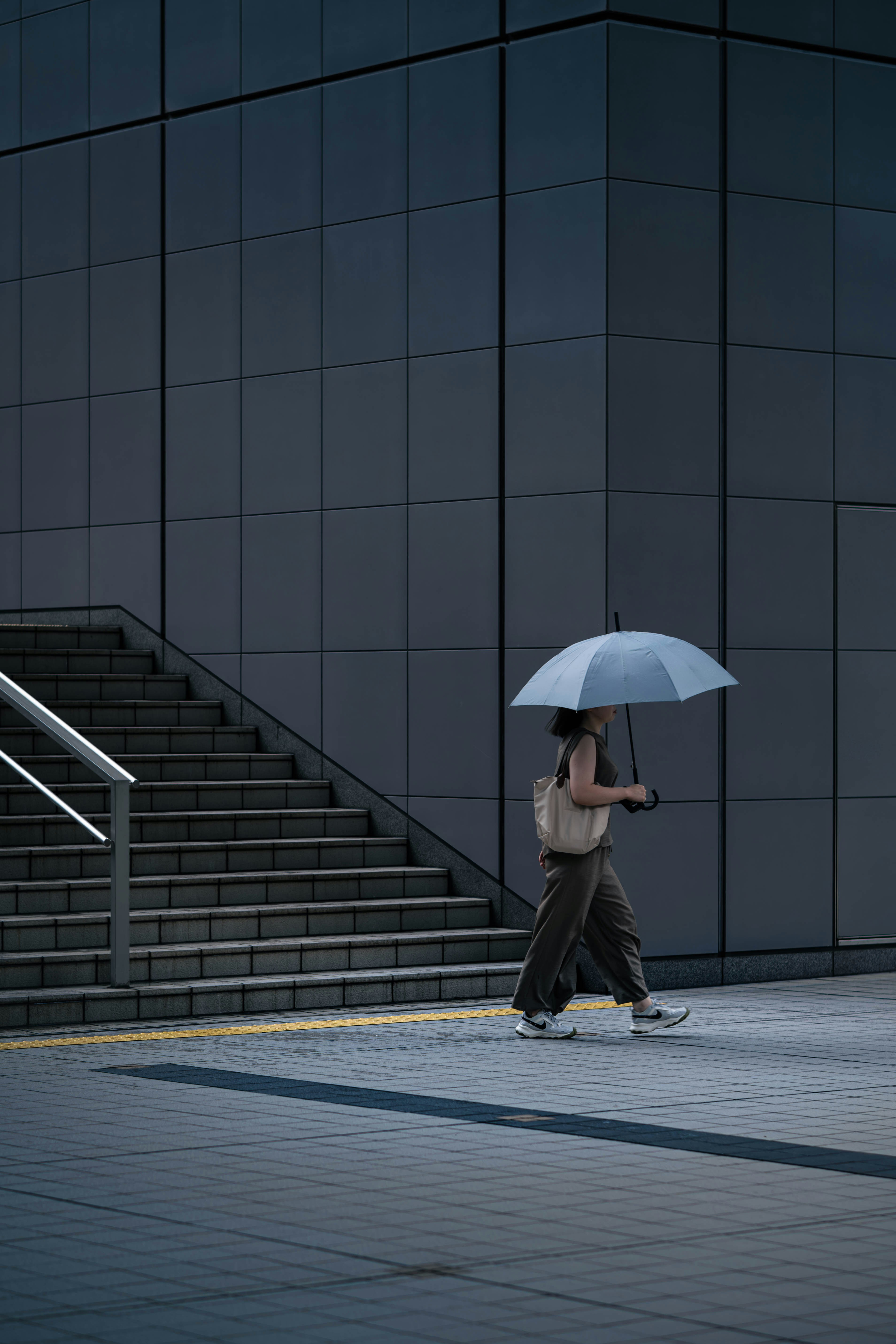 Umbrella in Motion: Quiet Walk Along a Modern Facade