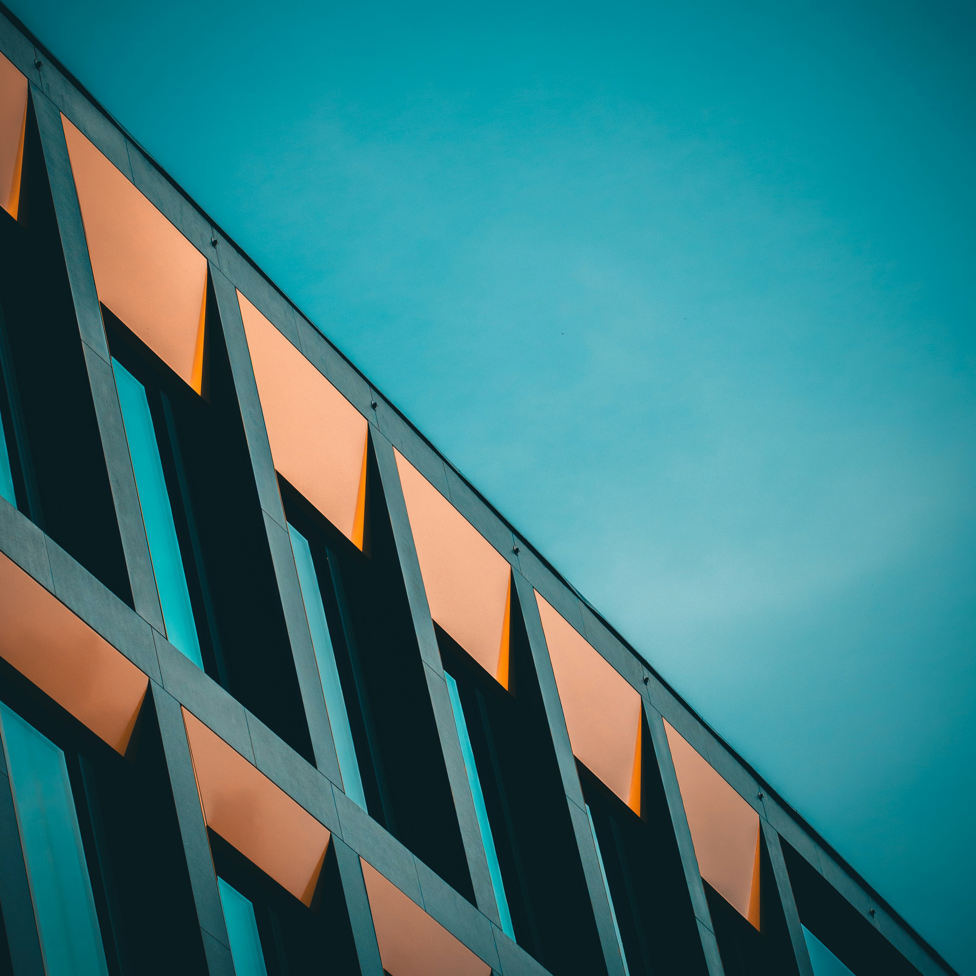 Diagonal Facade: Triangles of Sunlit Orange Against Teal Steel